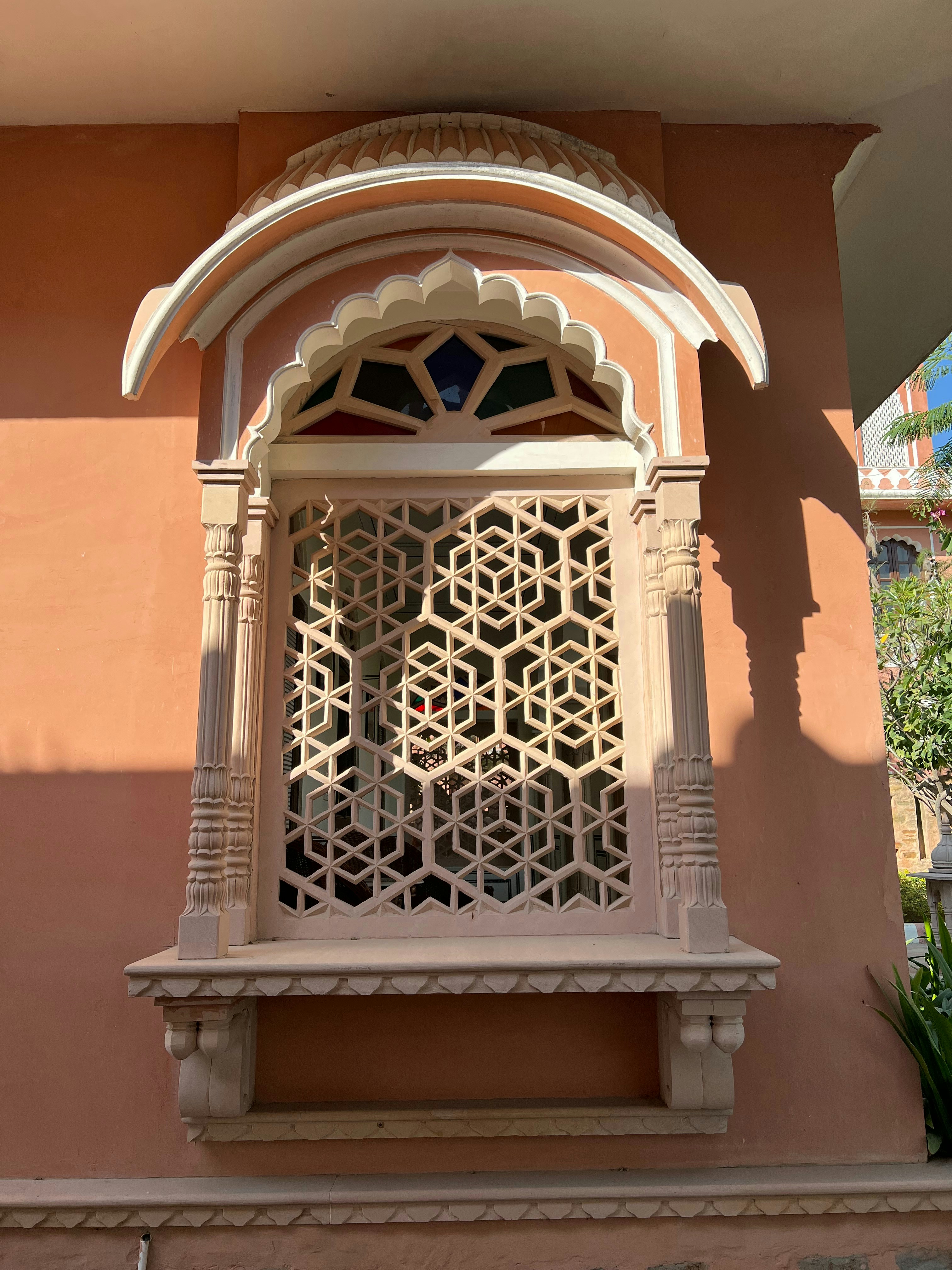 Geometric Lace under a Sunlit Arch on a Terracotta Façade