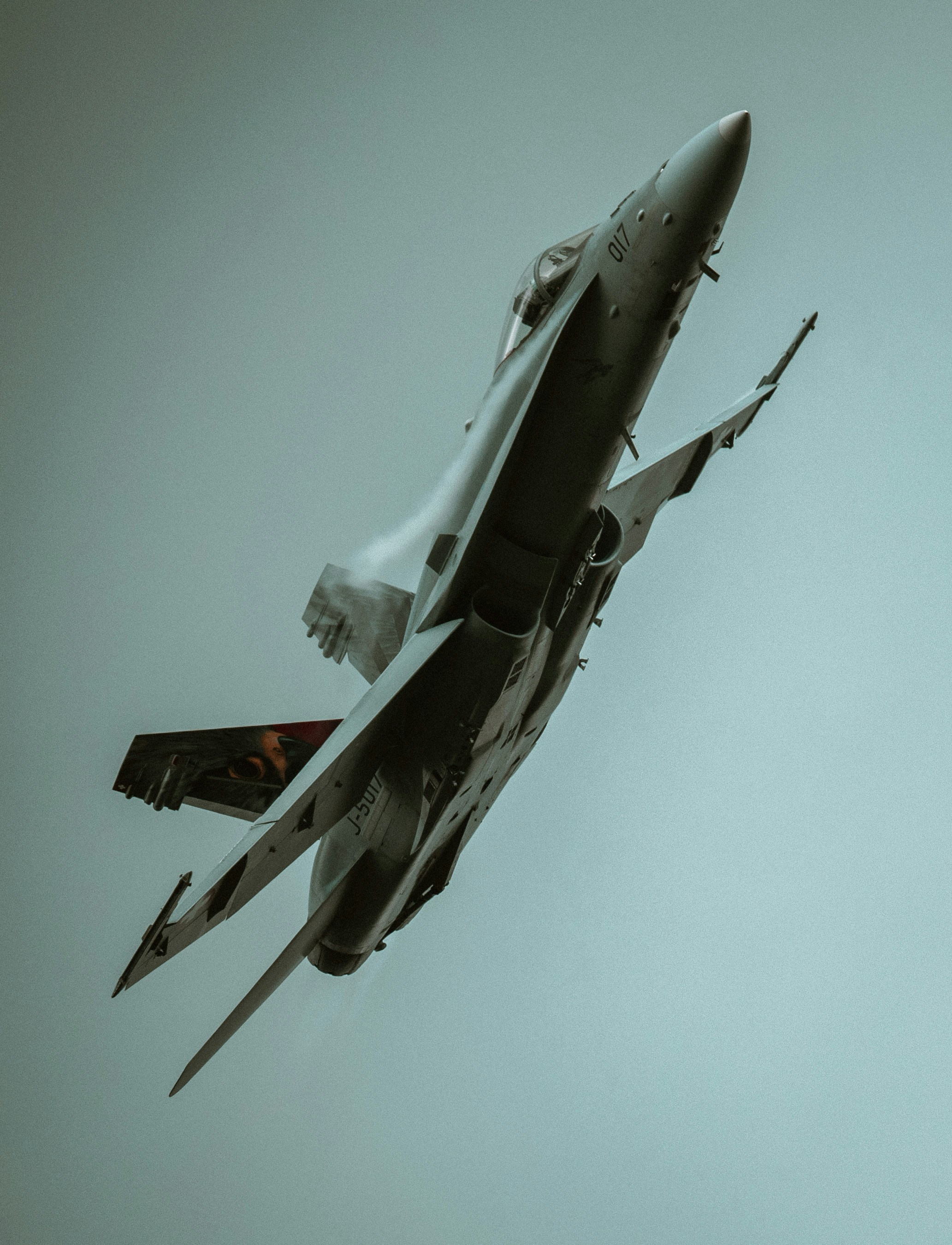 a fighter jet flying through a cloudy sky