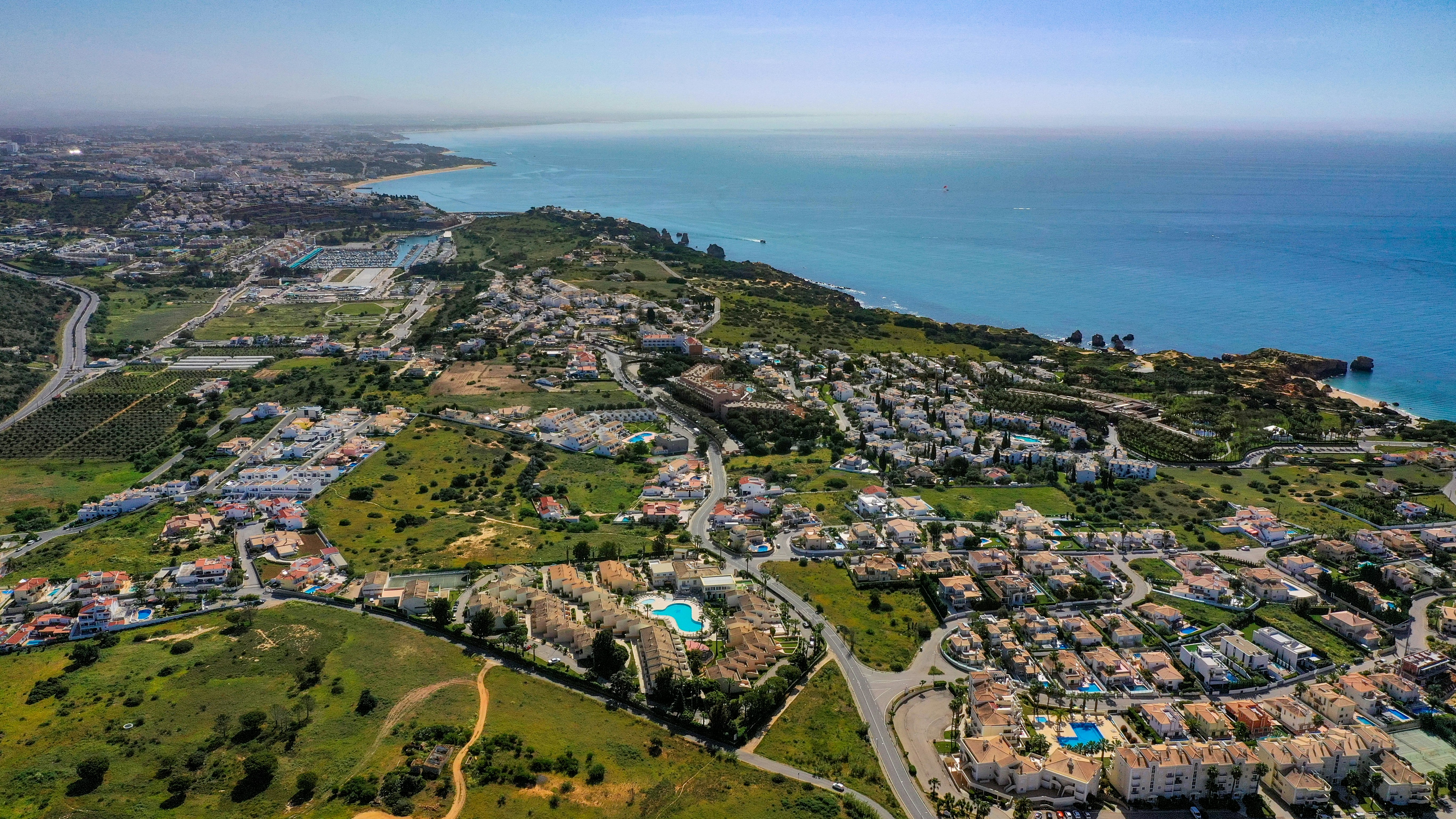 Aerial view of a coastal town where urban development meets the expansive sea under clear skies.