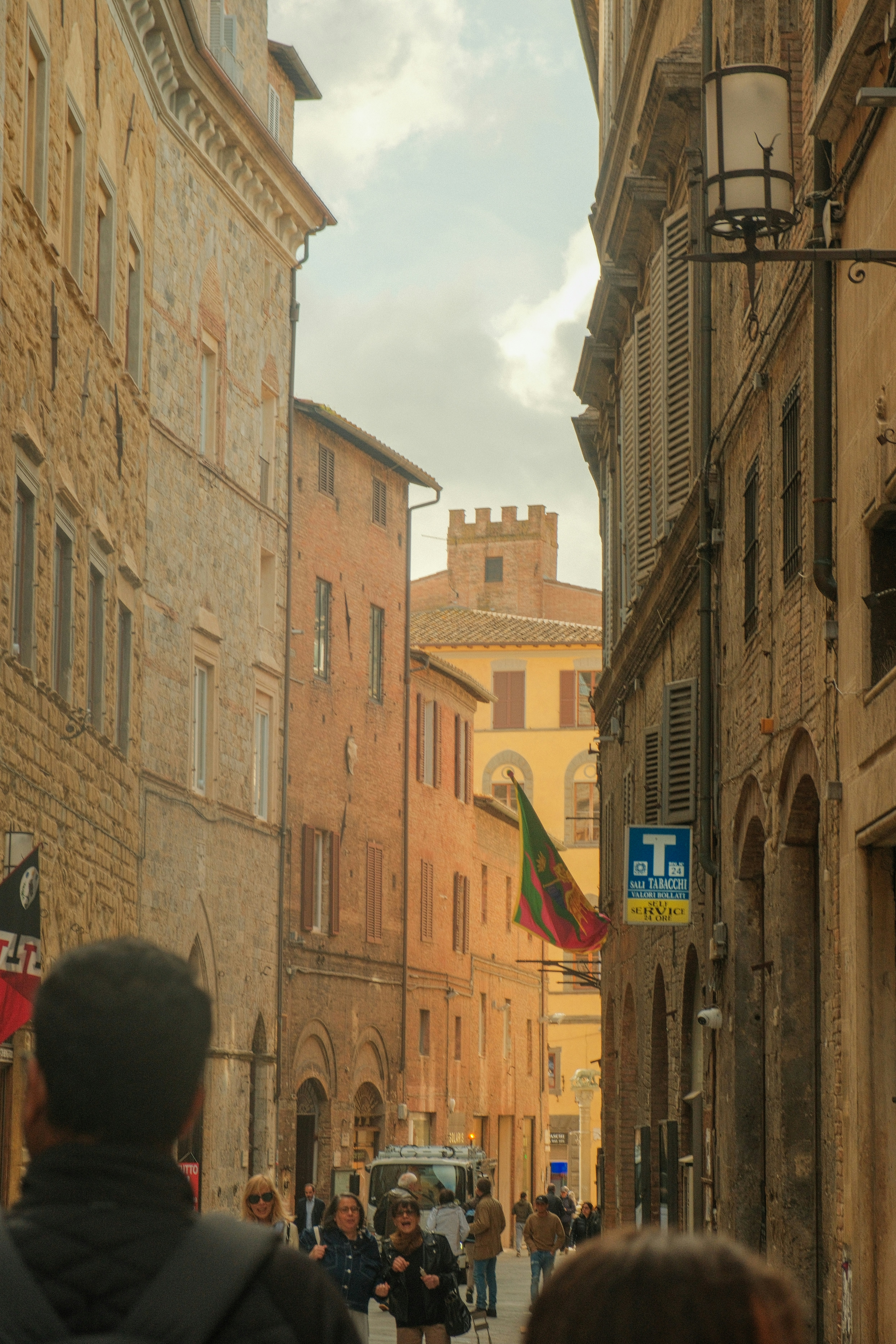 Golden Hour in a Tuscan Street: Flags, Stone, and Quiet Foot Traffic