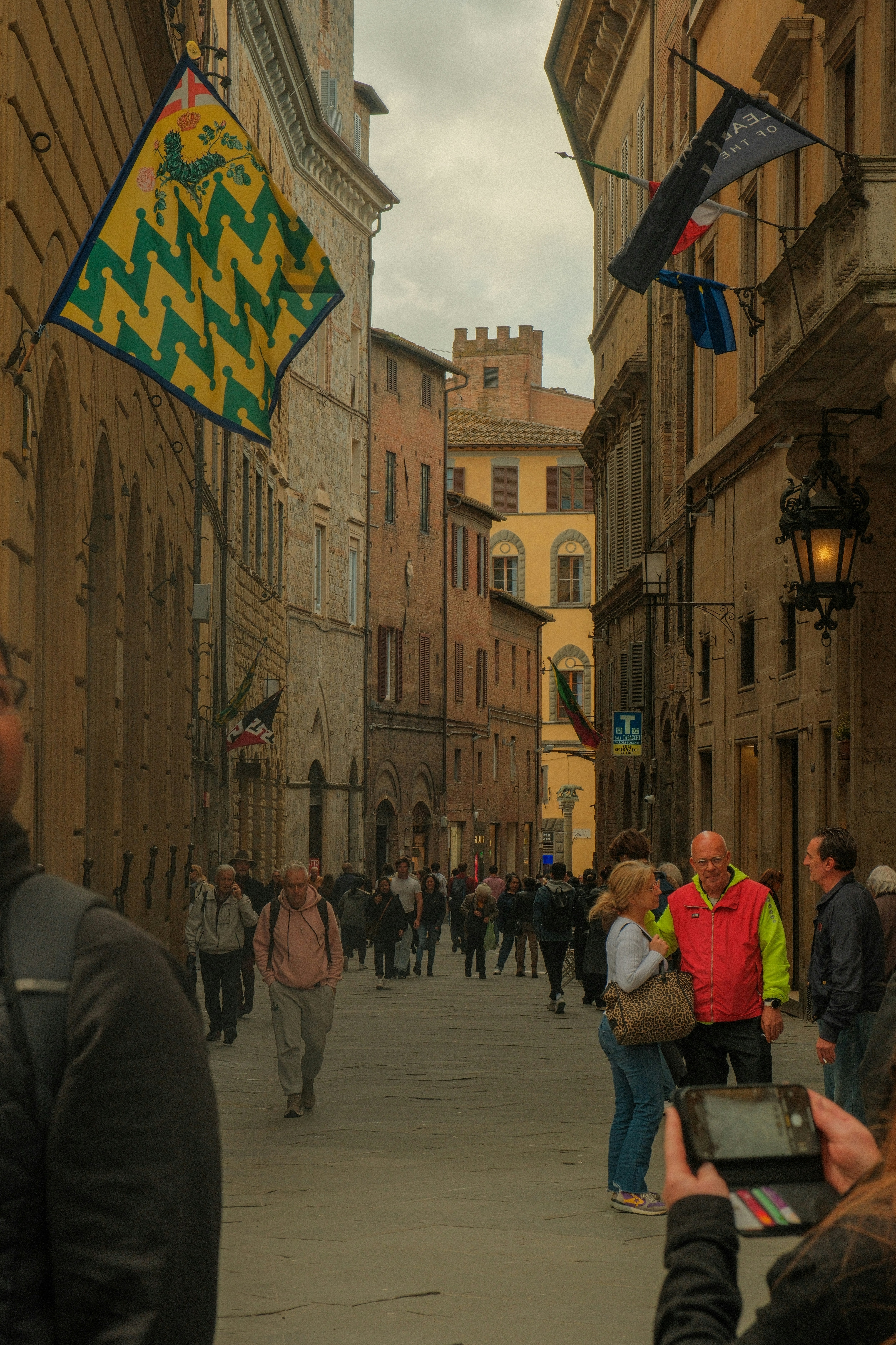 a crowd of people walking down a street next to tall buildings