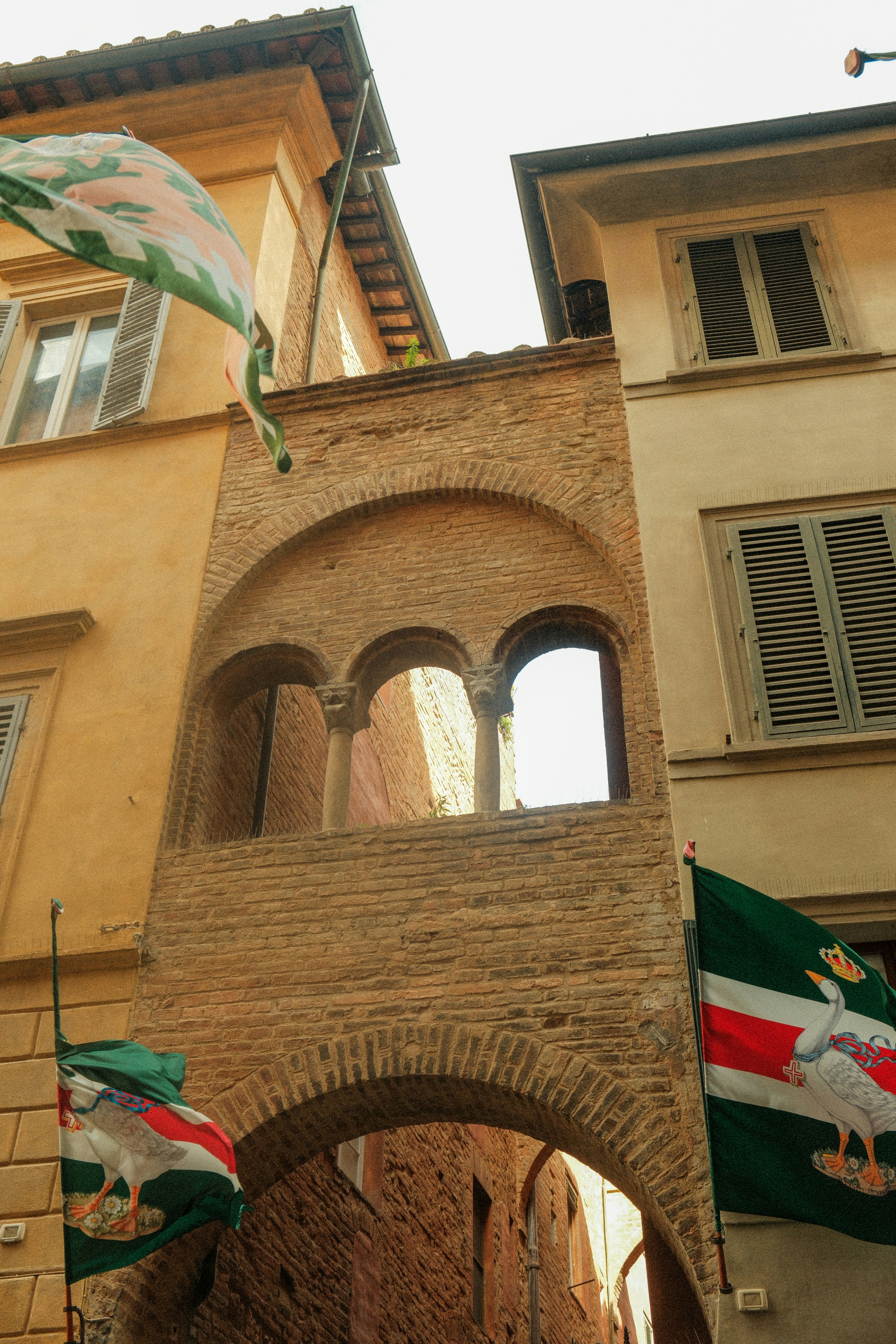 Flag-Touched Brick Arcades: A Quiet Italian Street Corridor