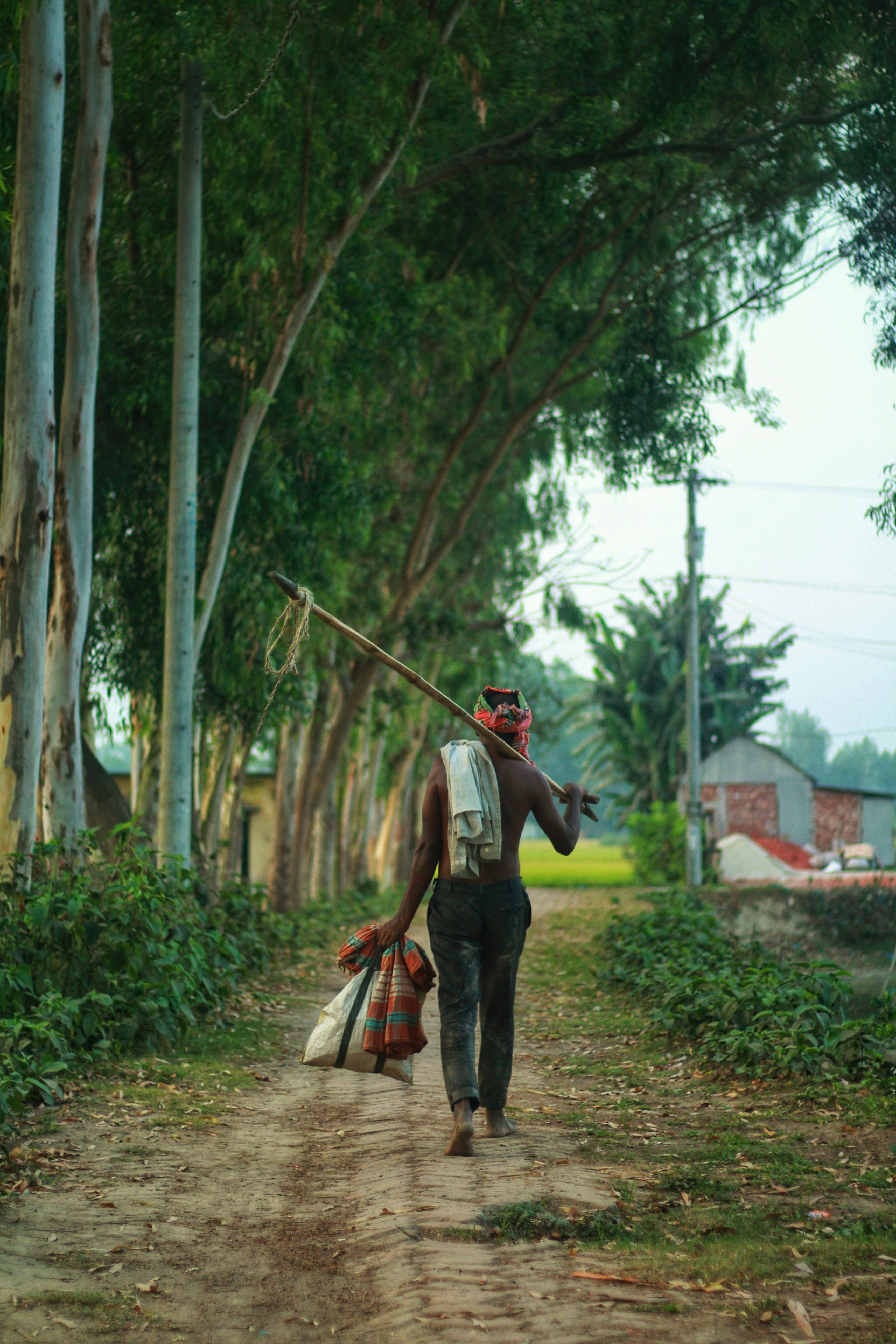 A man walking down a dirt road holding a baseball bat photo – Free ...
