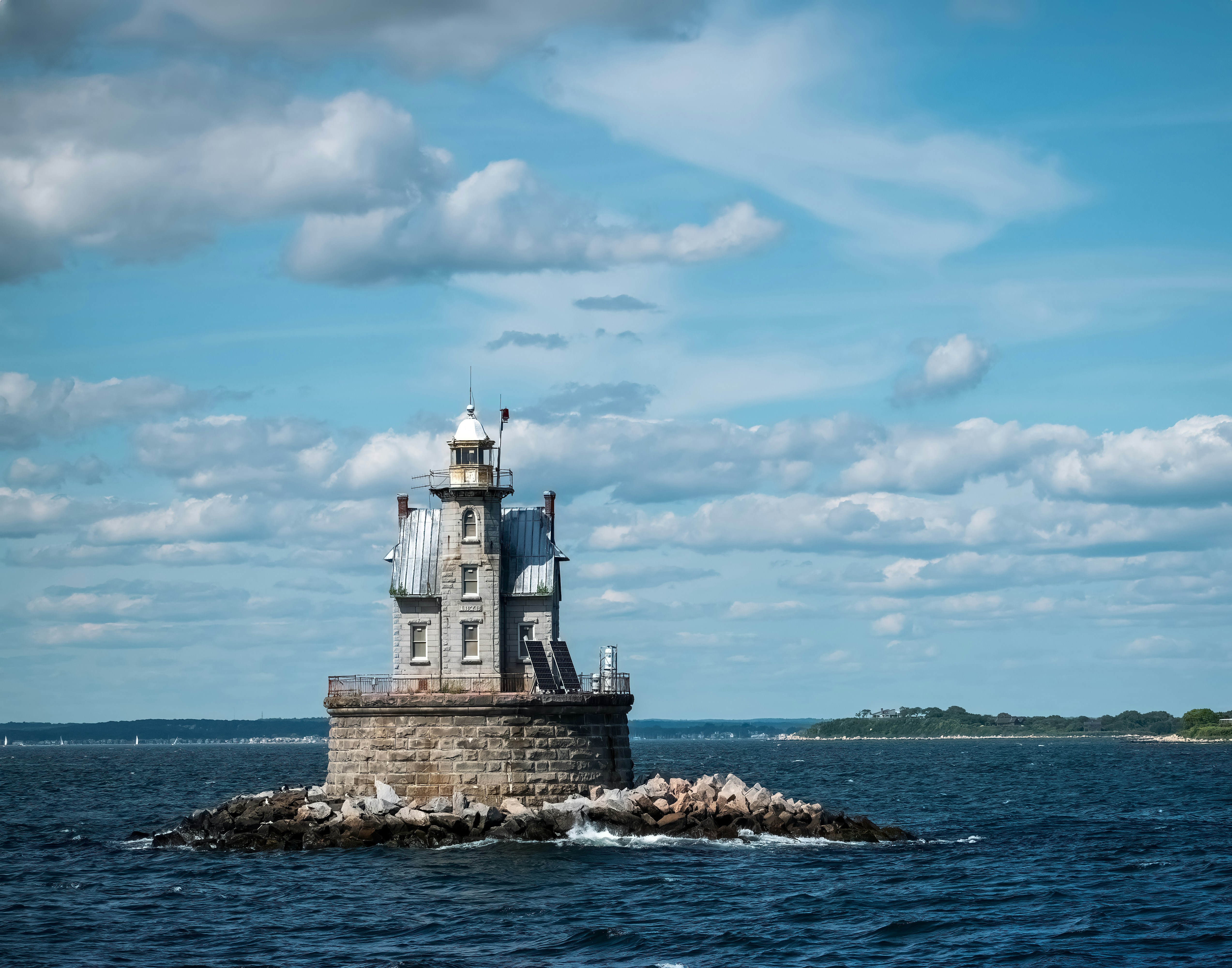 A lighthouse on a small island in the middle of the ocean photo – Free ...