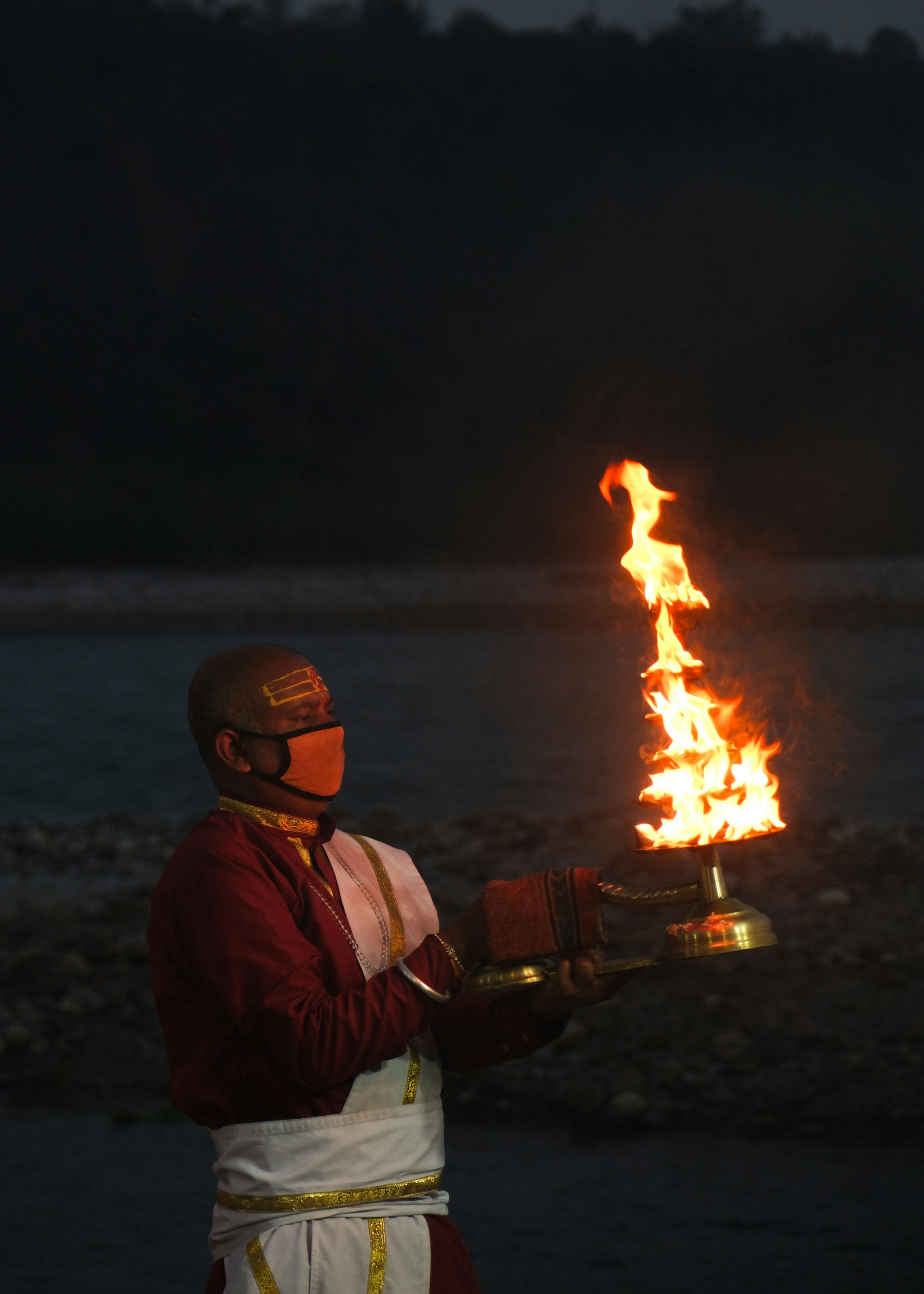 Torchbearer at dusk: ritual flame in the riverbank