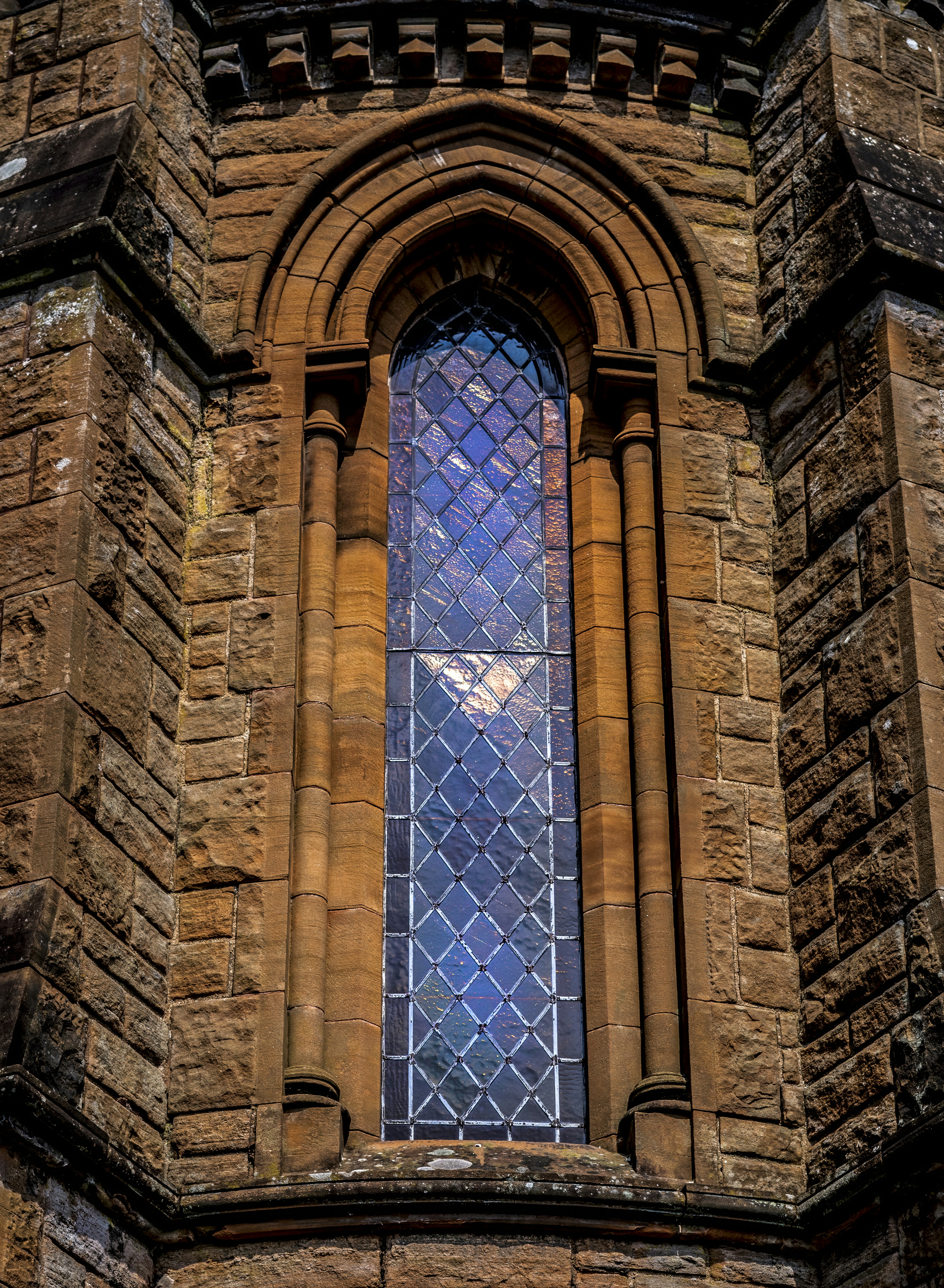 Azure Diamond-Pane Lancet Window Framed by Time-Worn Sandstone