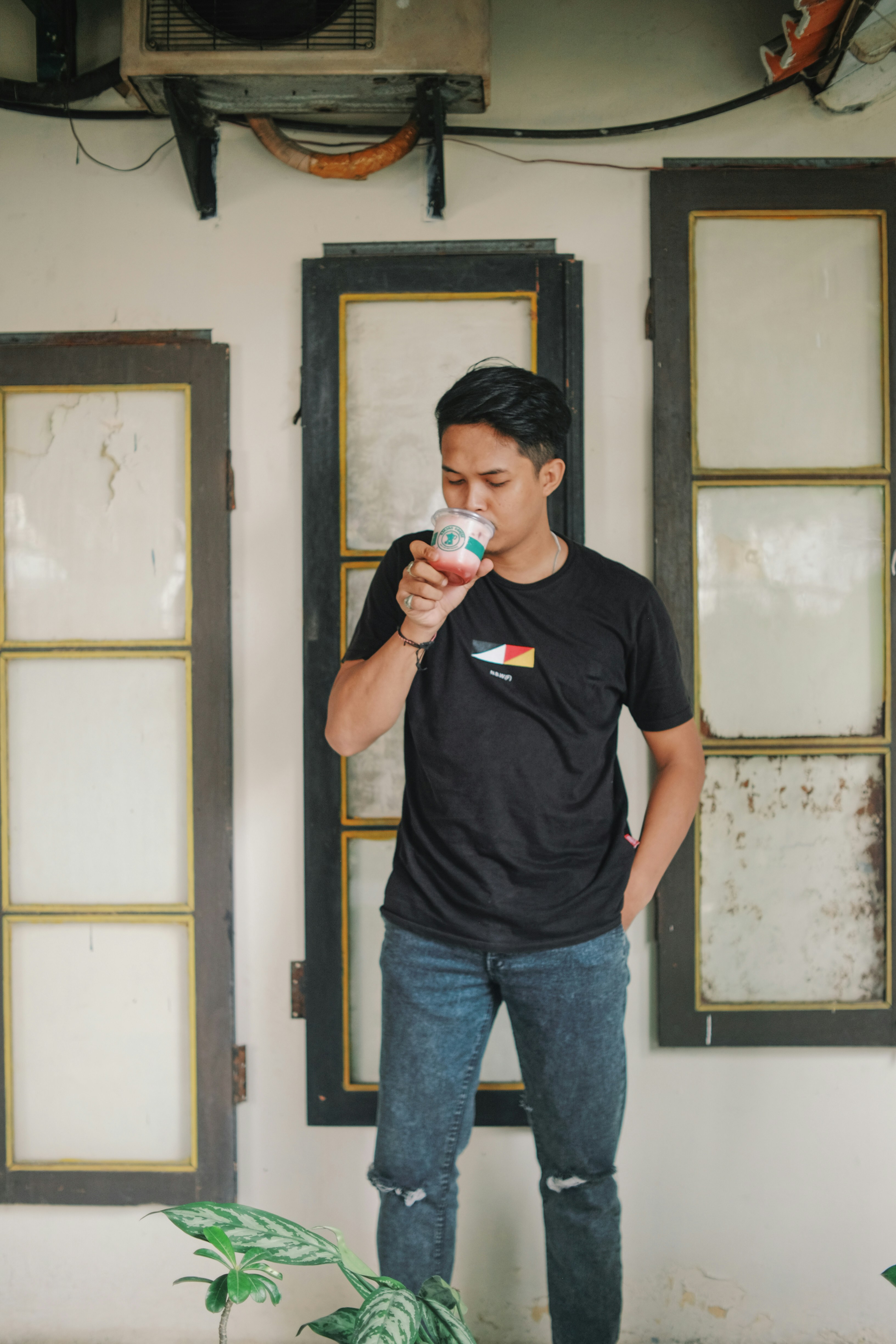 A man standing in front of a wall drinking from a cup photo – Free Food ...