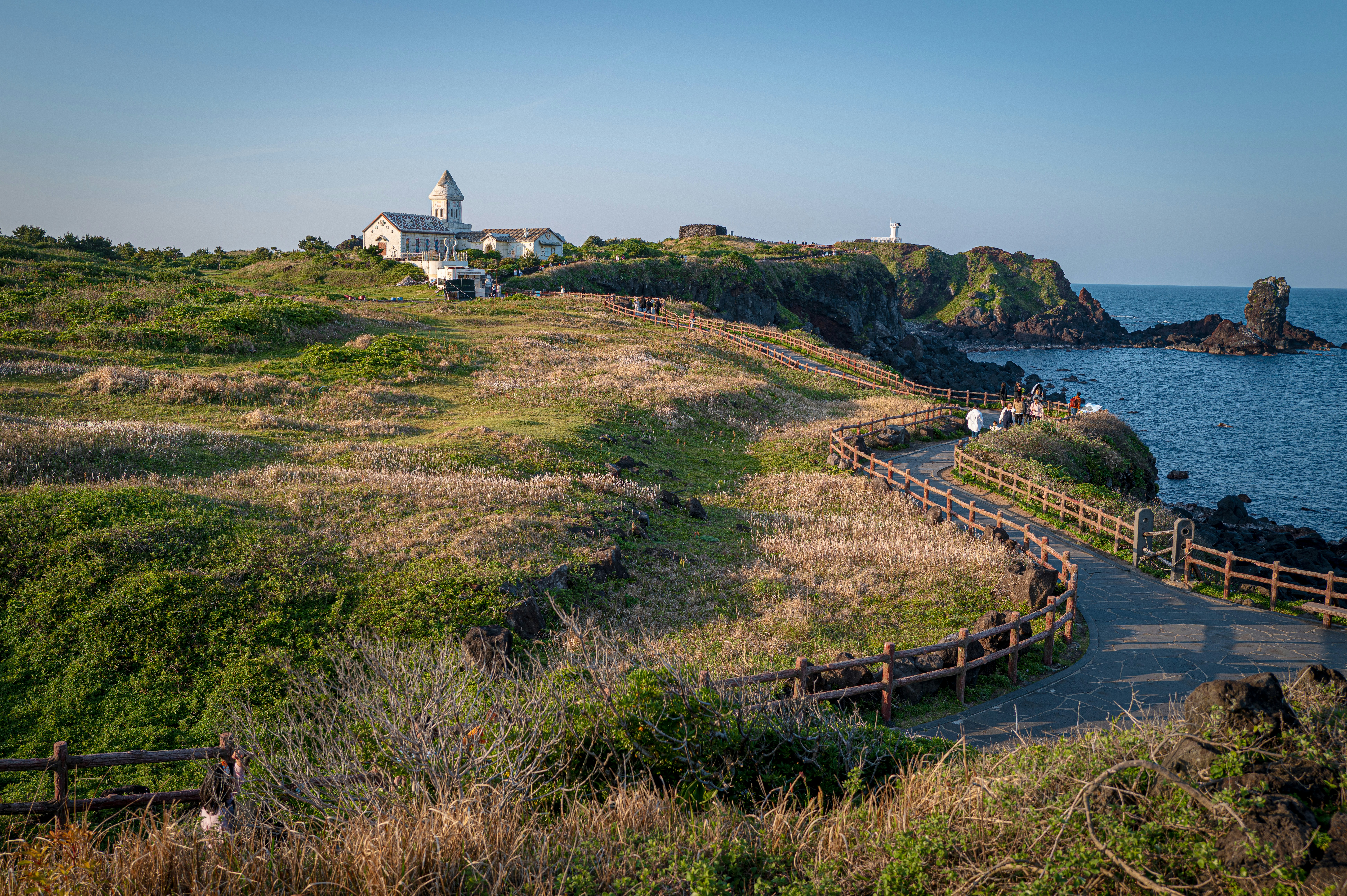 A path leading to a lighthouse on a hill next to the ocean photo – Free ...