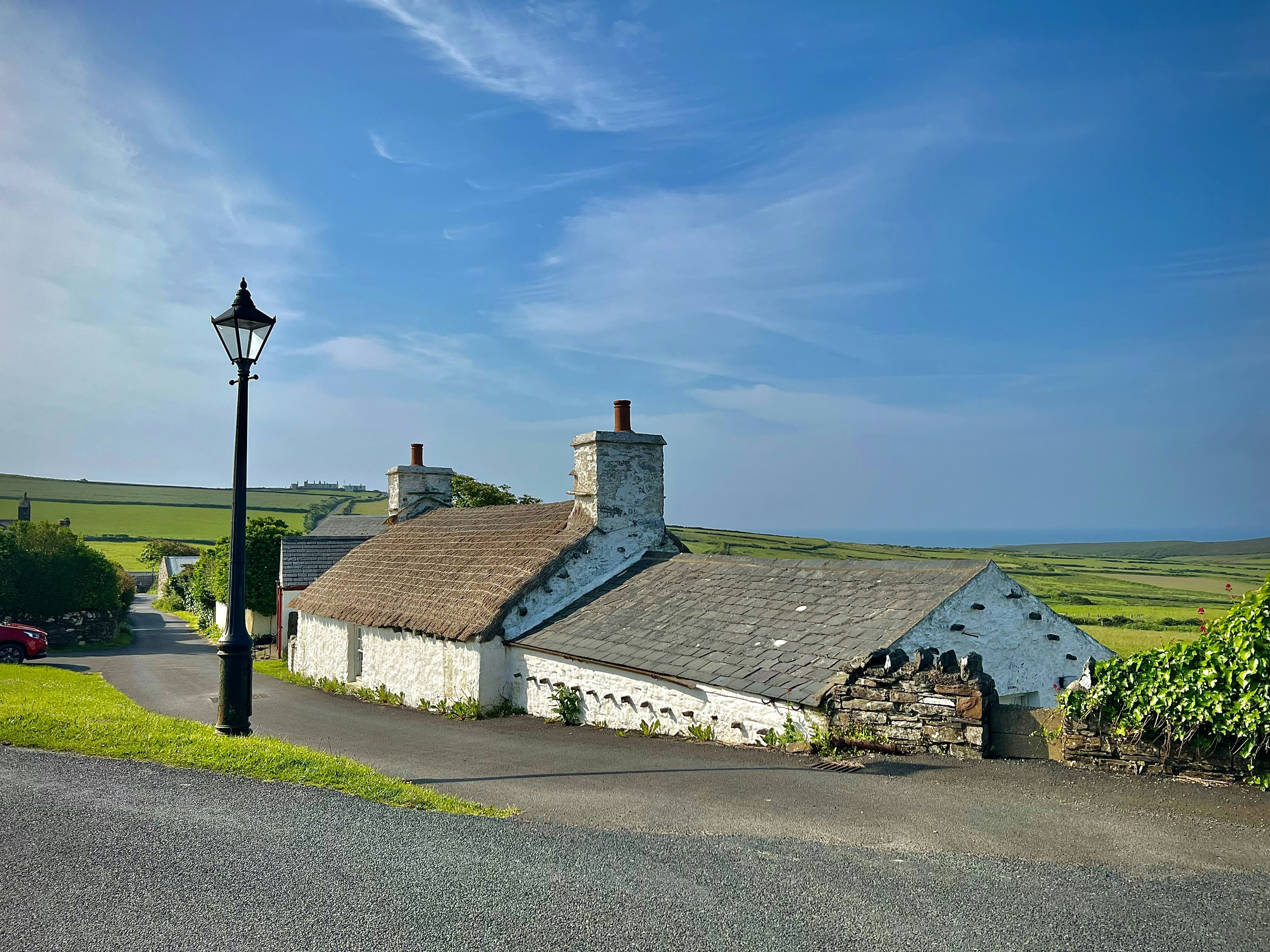 Charming white-washed cottages nestled in a lush green landscape under a clear blue sky, showcasing a blend of rural architecture and natural beauty.