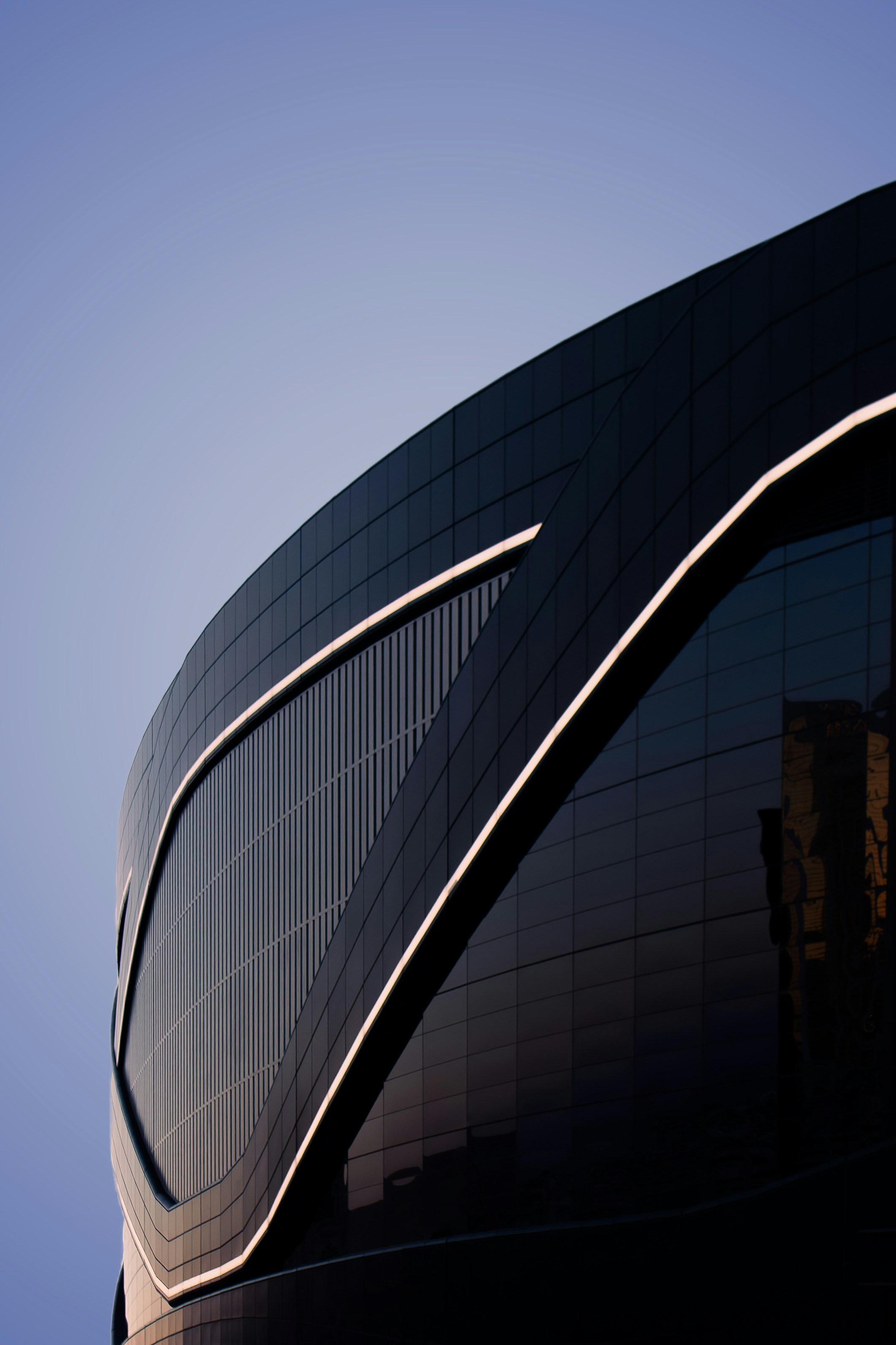 A building with a curved roof and a blue sky in the background photo ...