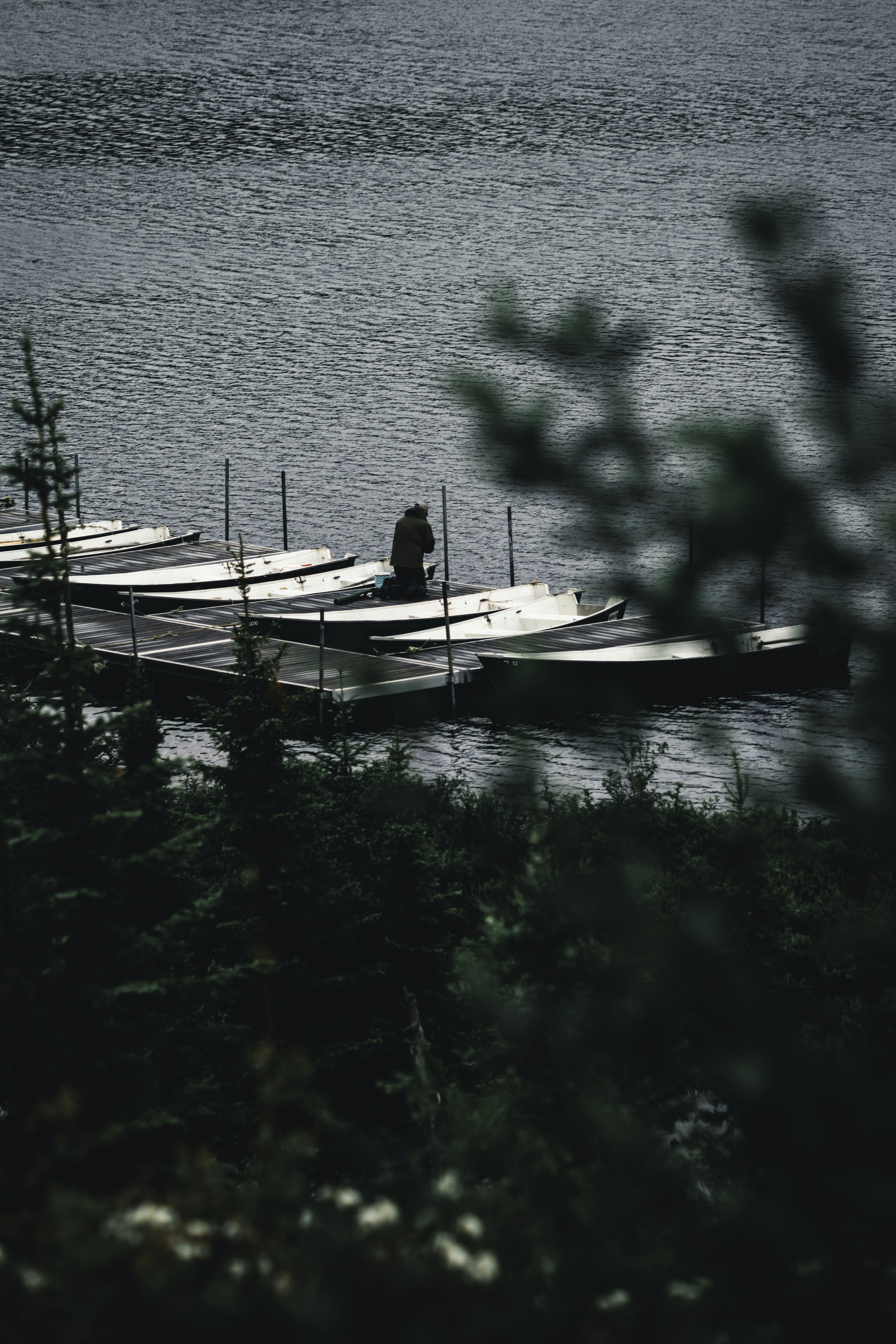 Dusk at the Quiet Dock: A solitary figure among rowboats
