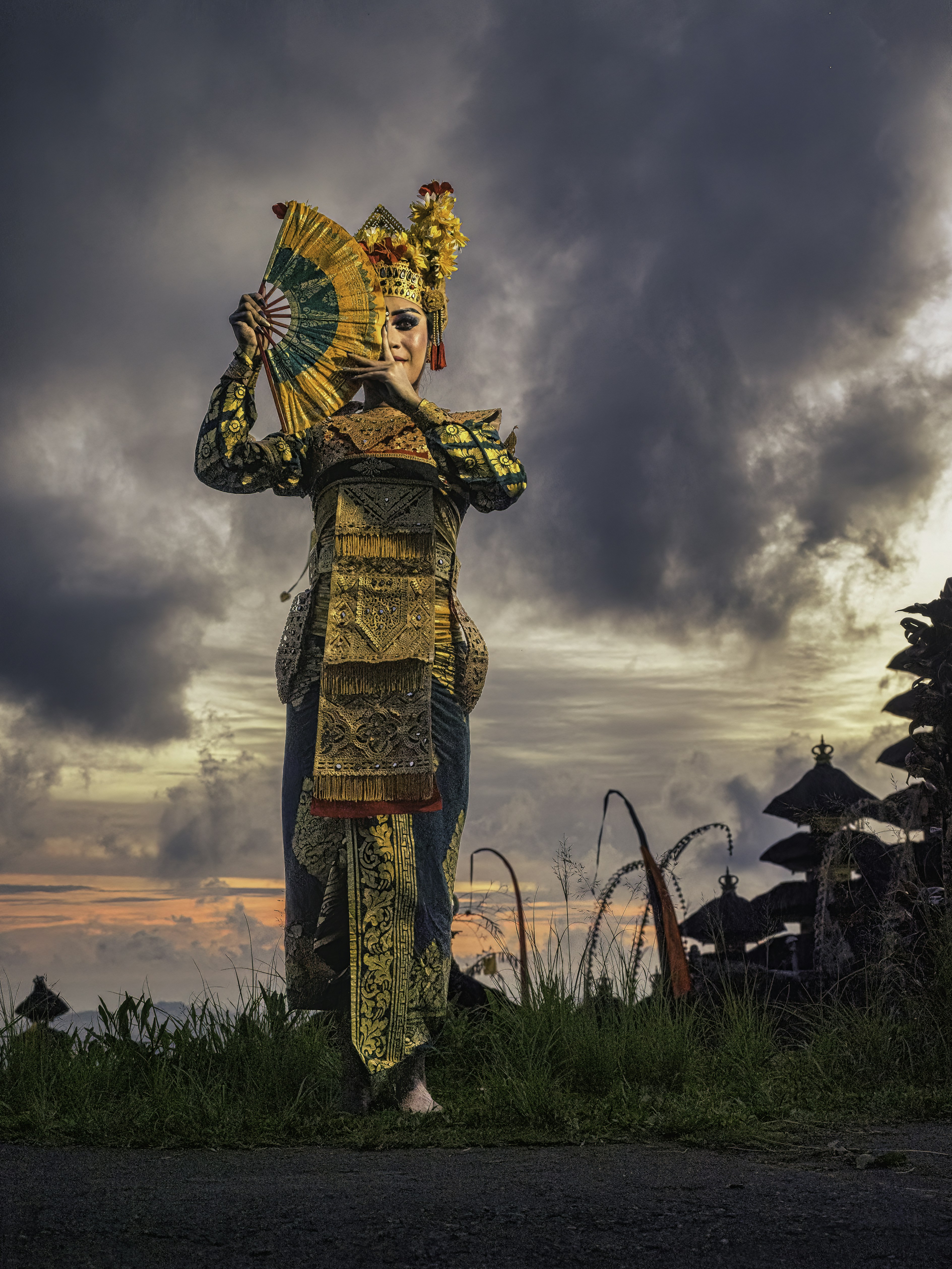 A beautiful young woman in traditional dress is standing with sunset near a temple