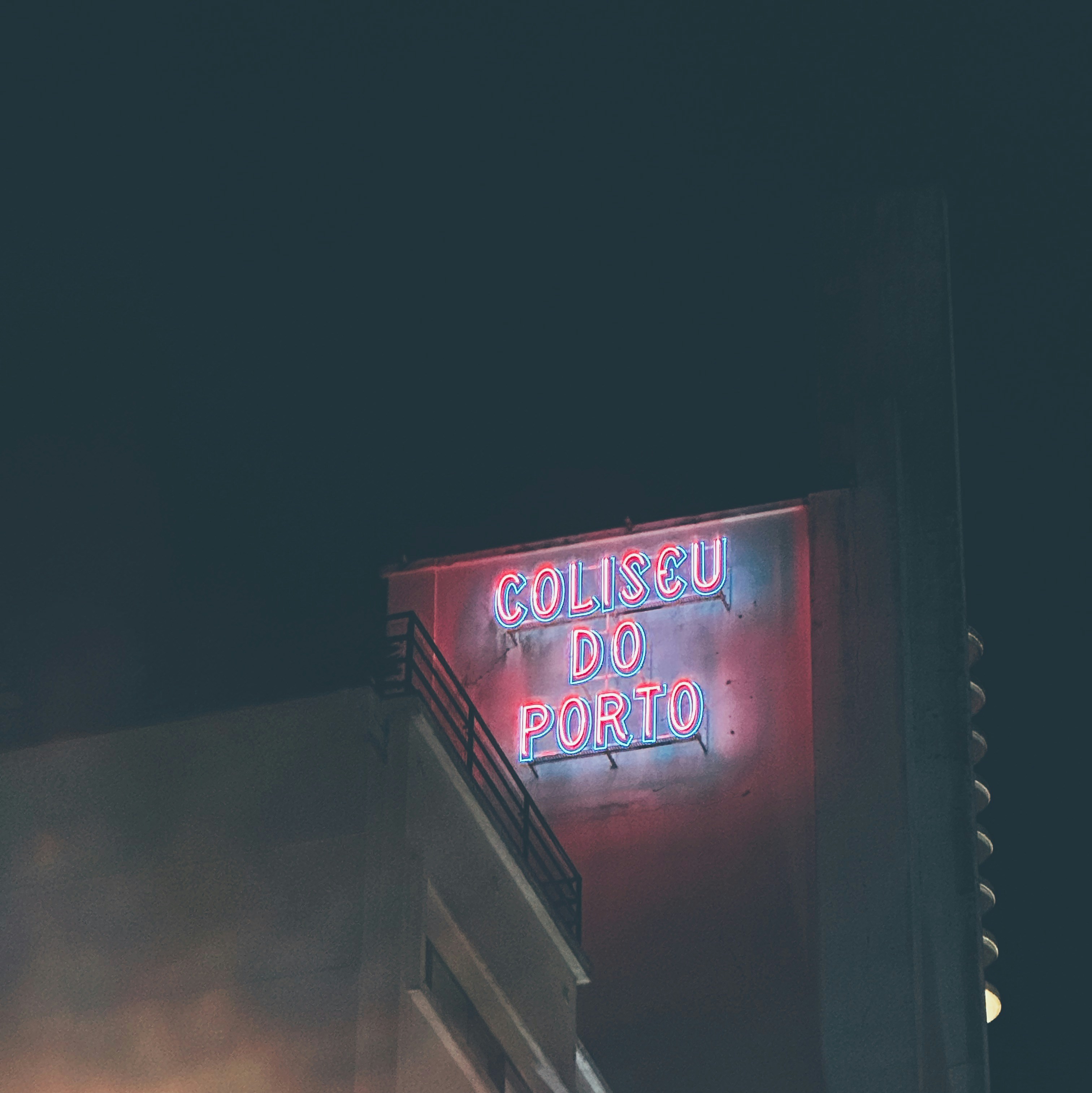 Illuminated sign reading 'COLISEU DO PORTO' against a night sky, highlighting the vibrant nightlife of the city.