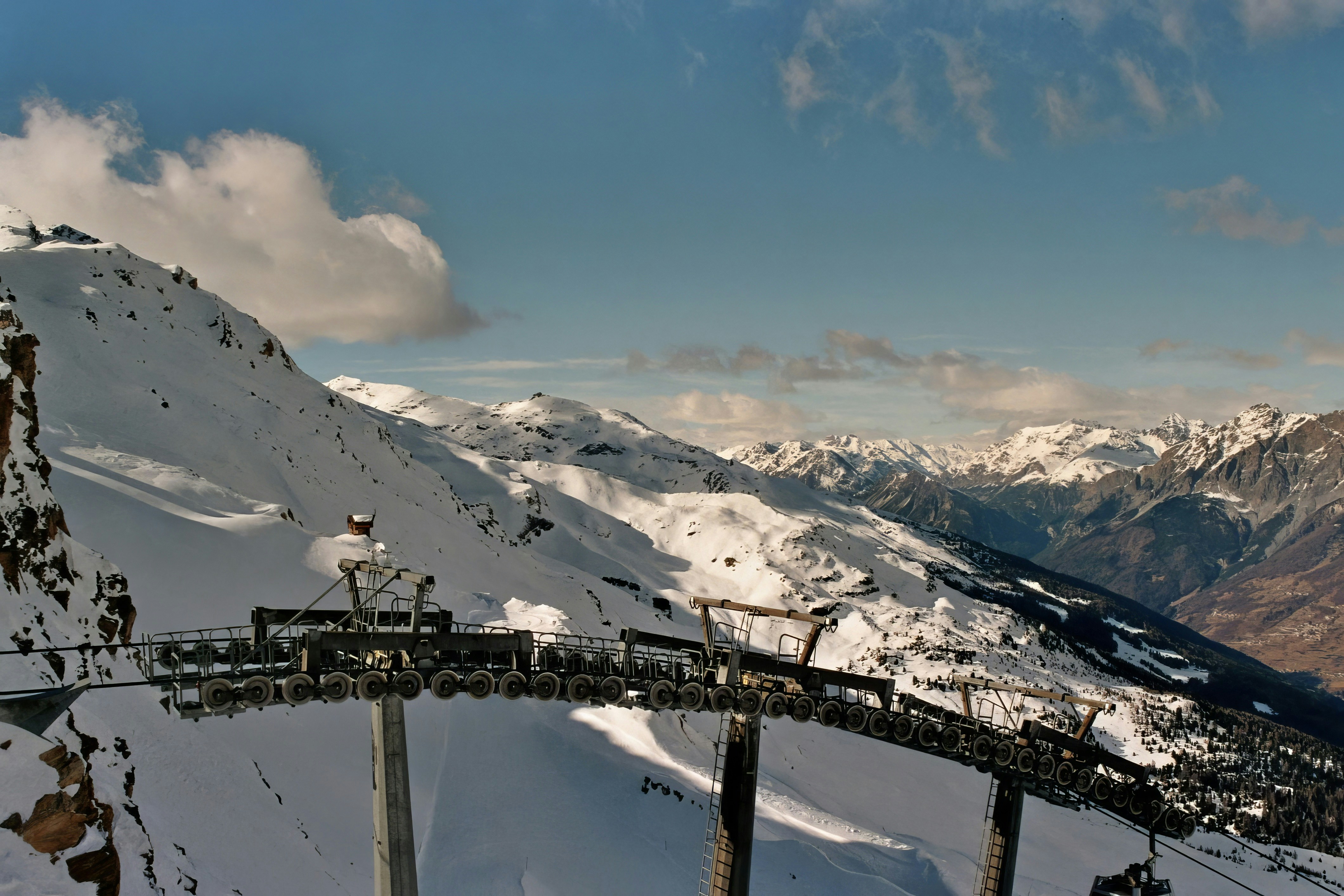 Ski lift ascending a snow-covered mountain range under a clear blue sky.