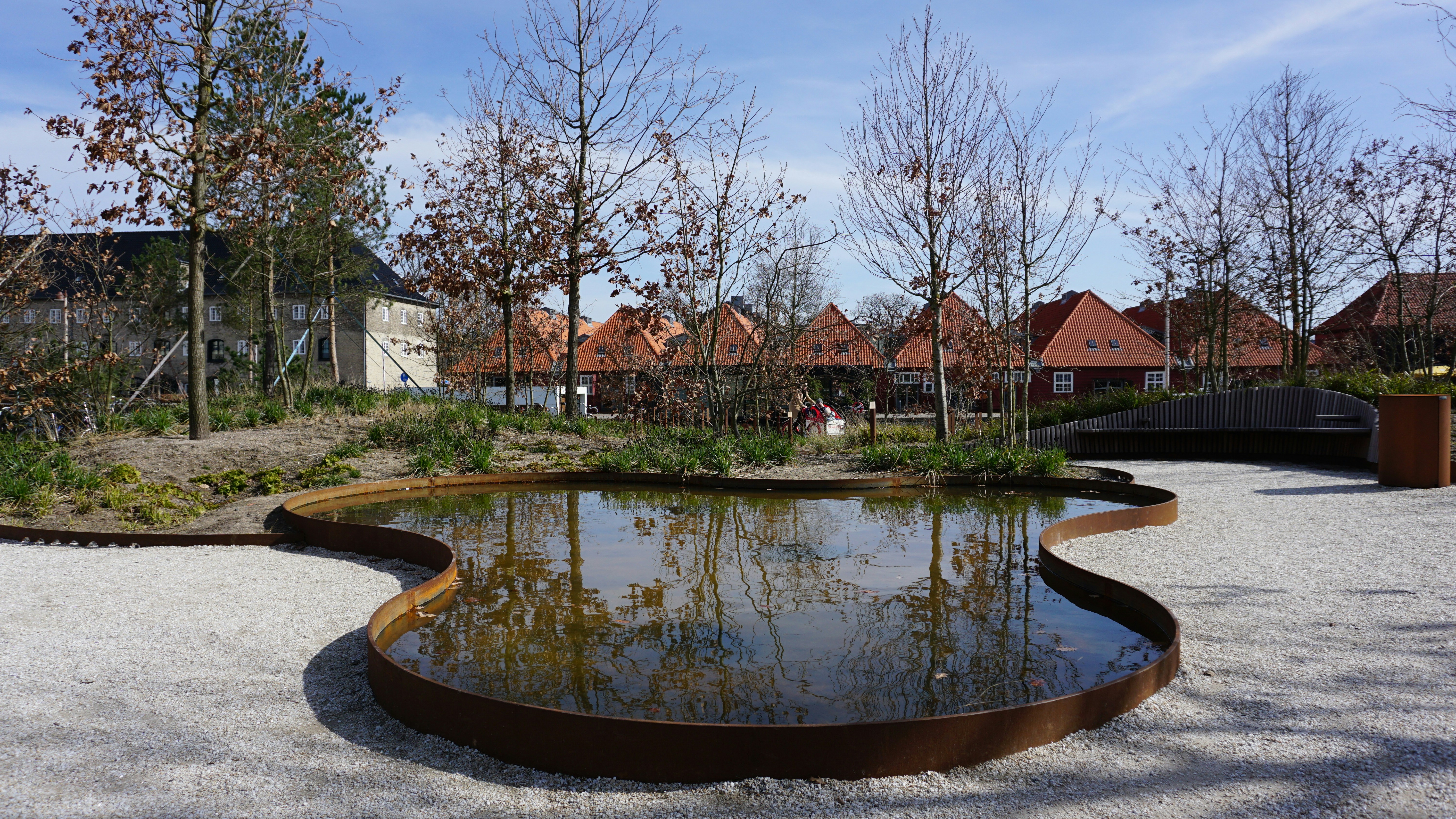Serpentine Pond in a Gravel Plaza Framed by Suburban Red-Tiled Homes