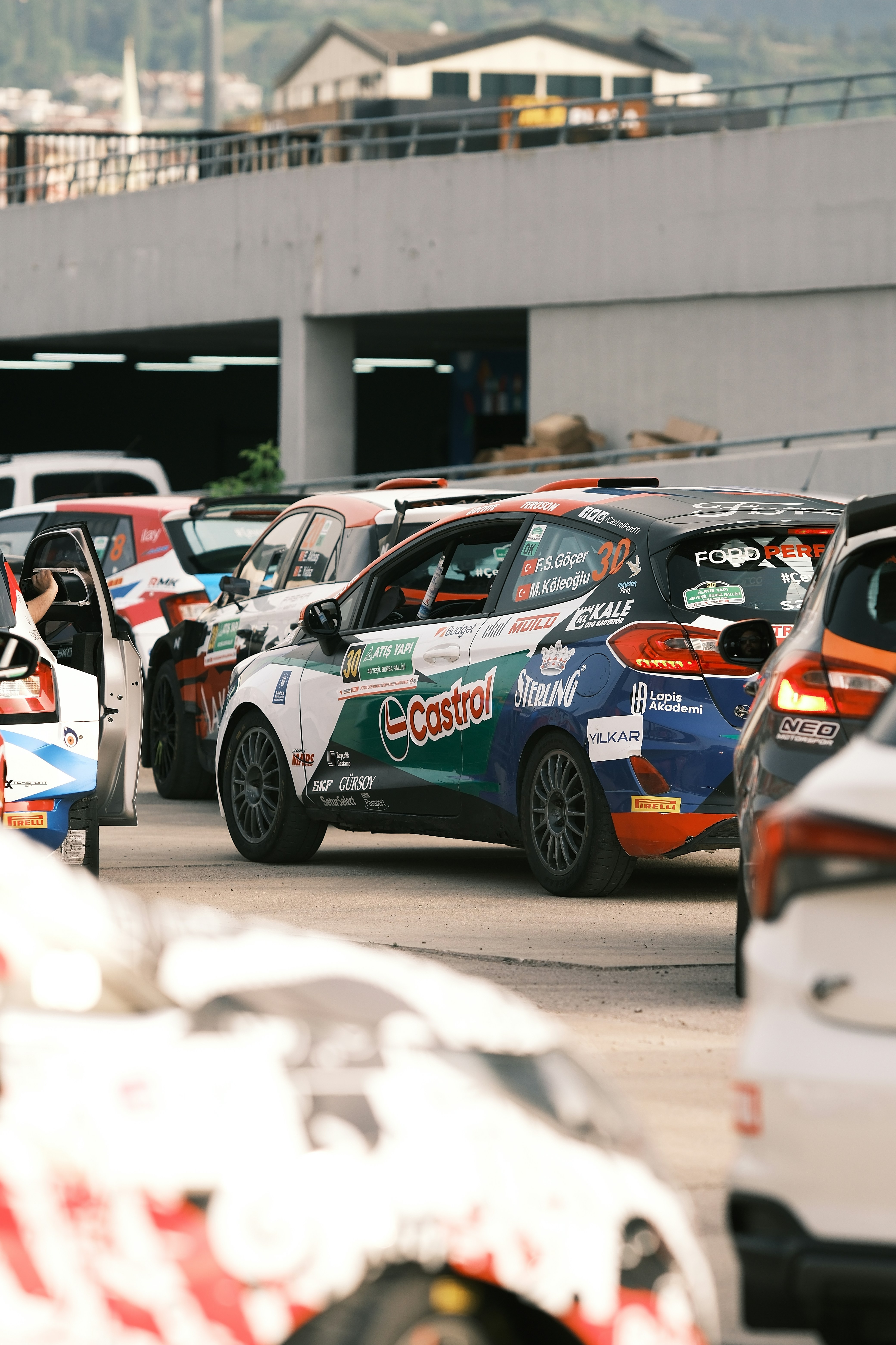 Castrol-Wrapped Rally Cars Converge in a Busy Pit Lane