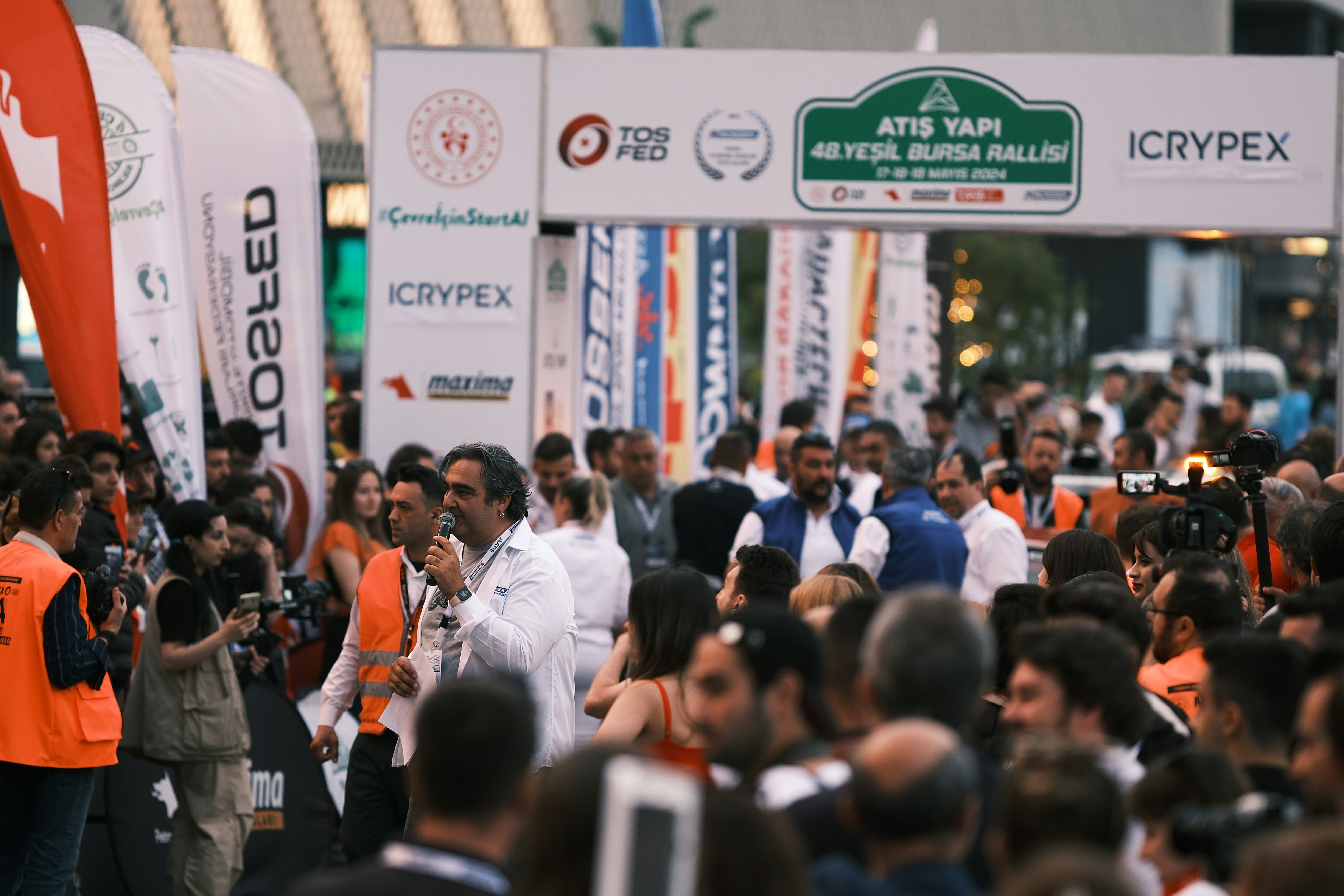 An annoucer in the event | a crowd of people standing around each other