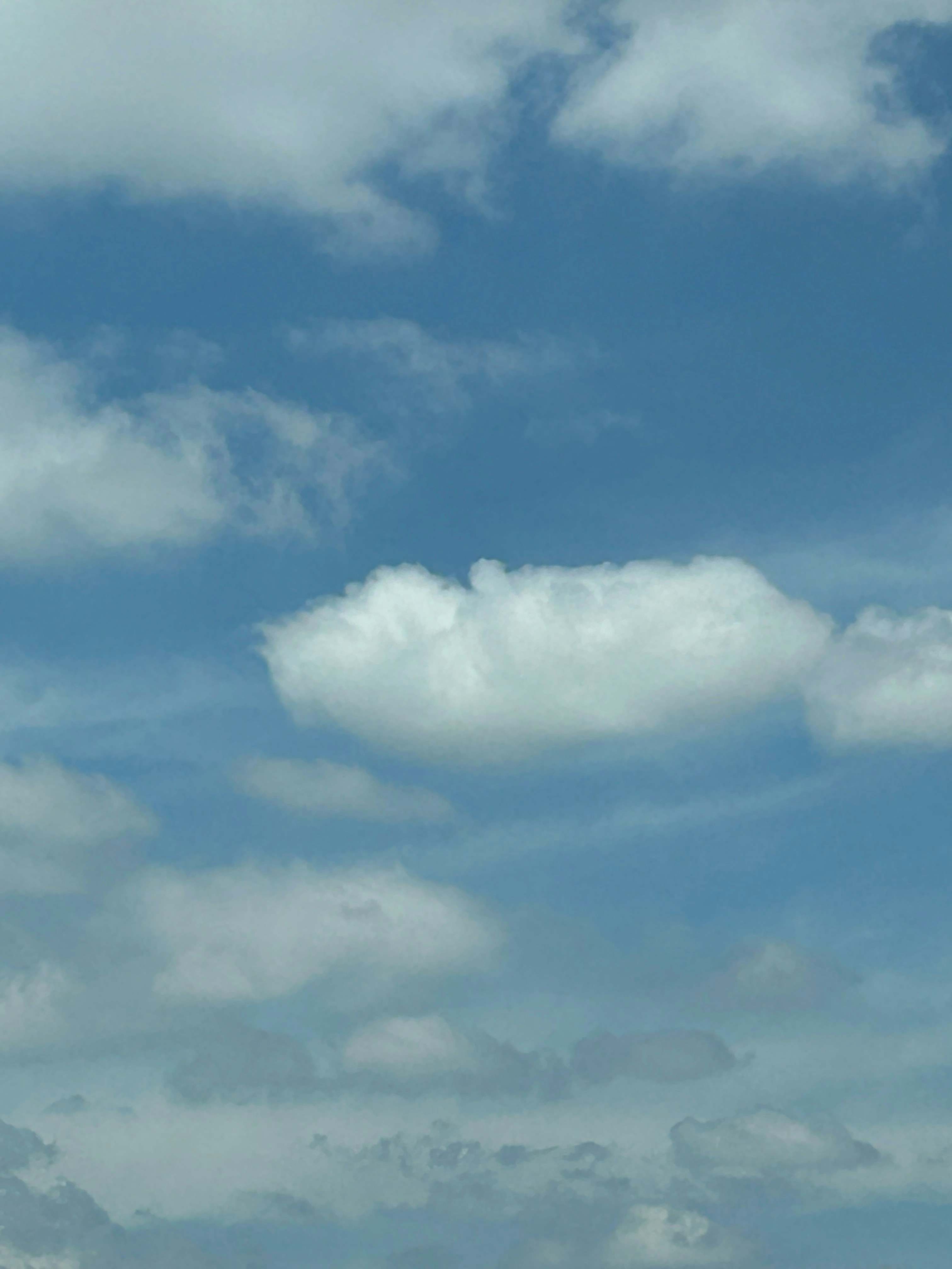 Clear blue sky with scattered white cumulus clouds, bathed in daylight. Emphasizes a tranquil, open-air atmosphere.