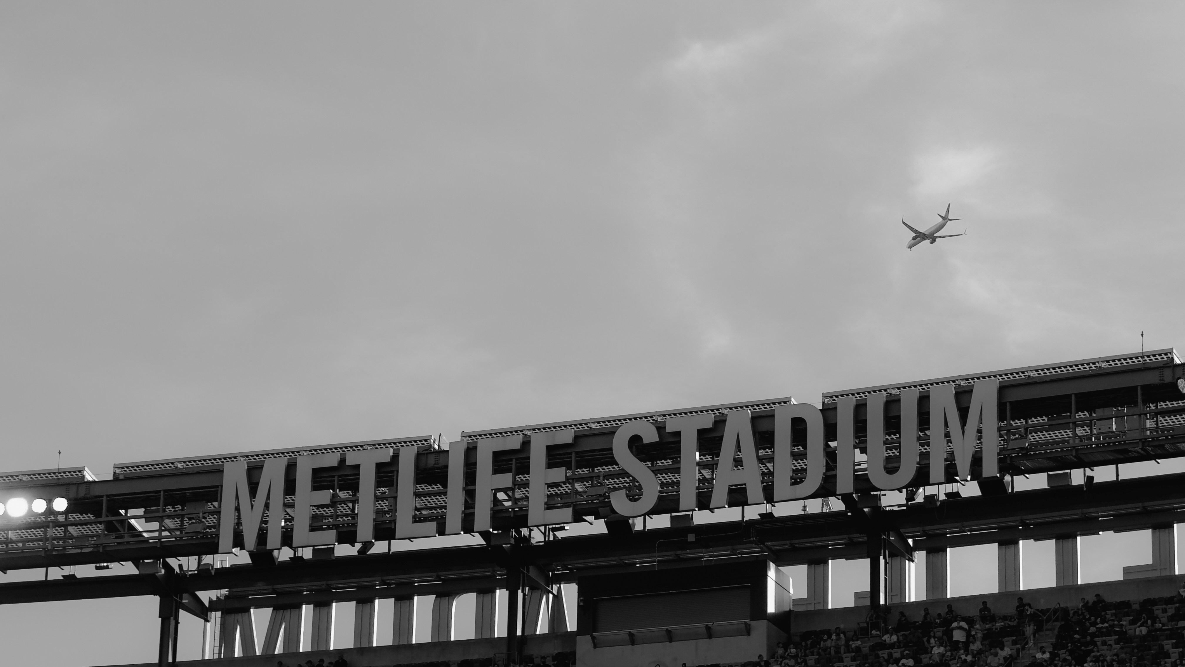 An airplane is flying over a stadium with a sign photo – Free Stadium ...