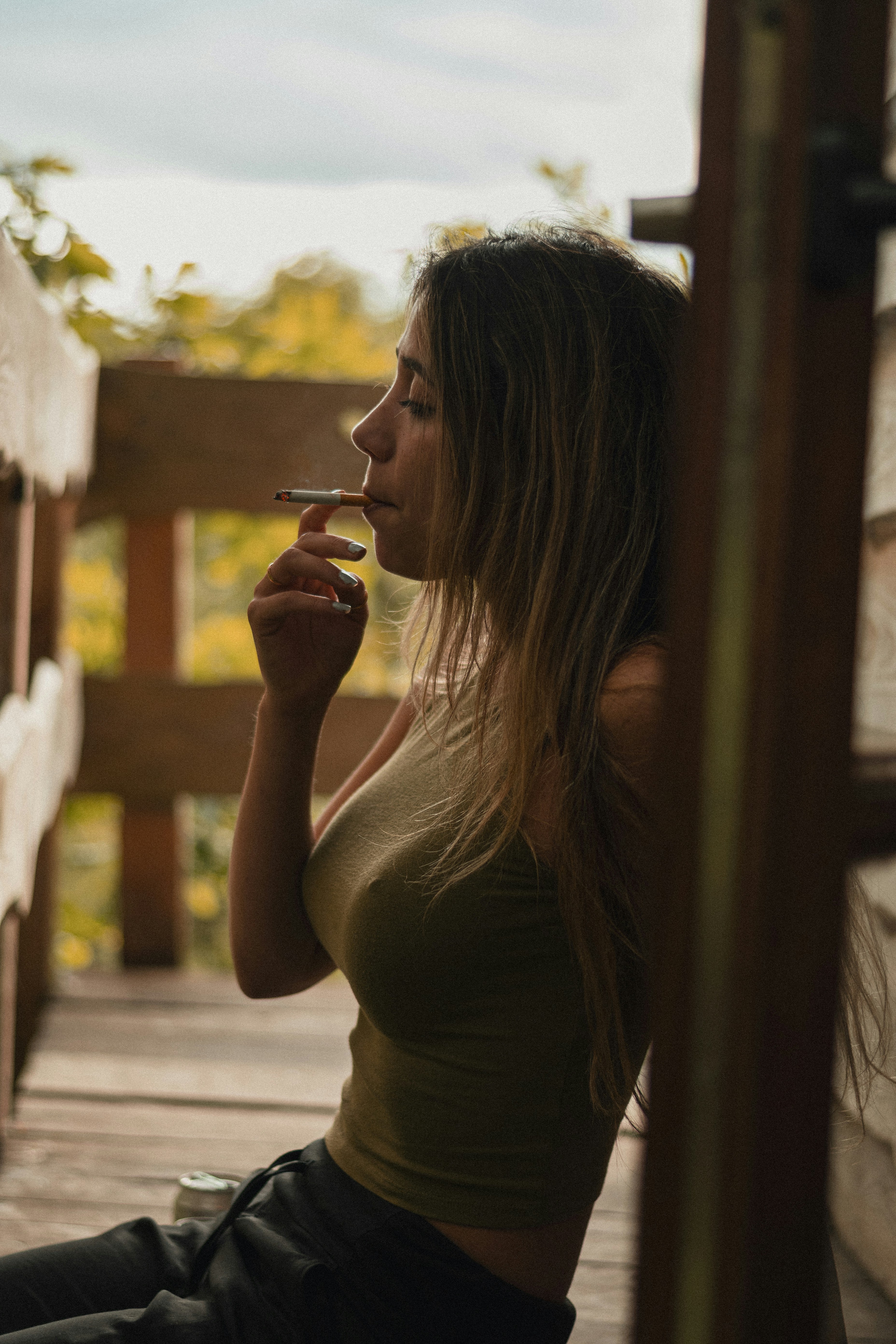 A woman sitting on a porch smoking a cigarette photo – Free Forest ...
