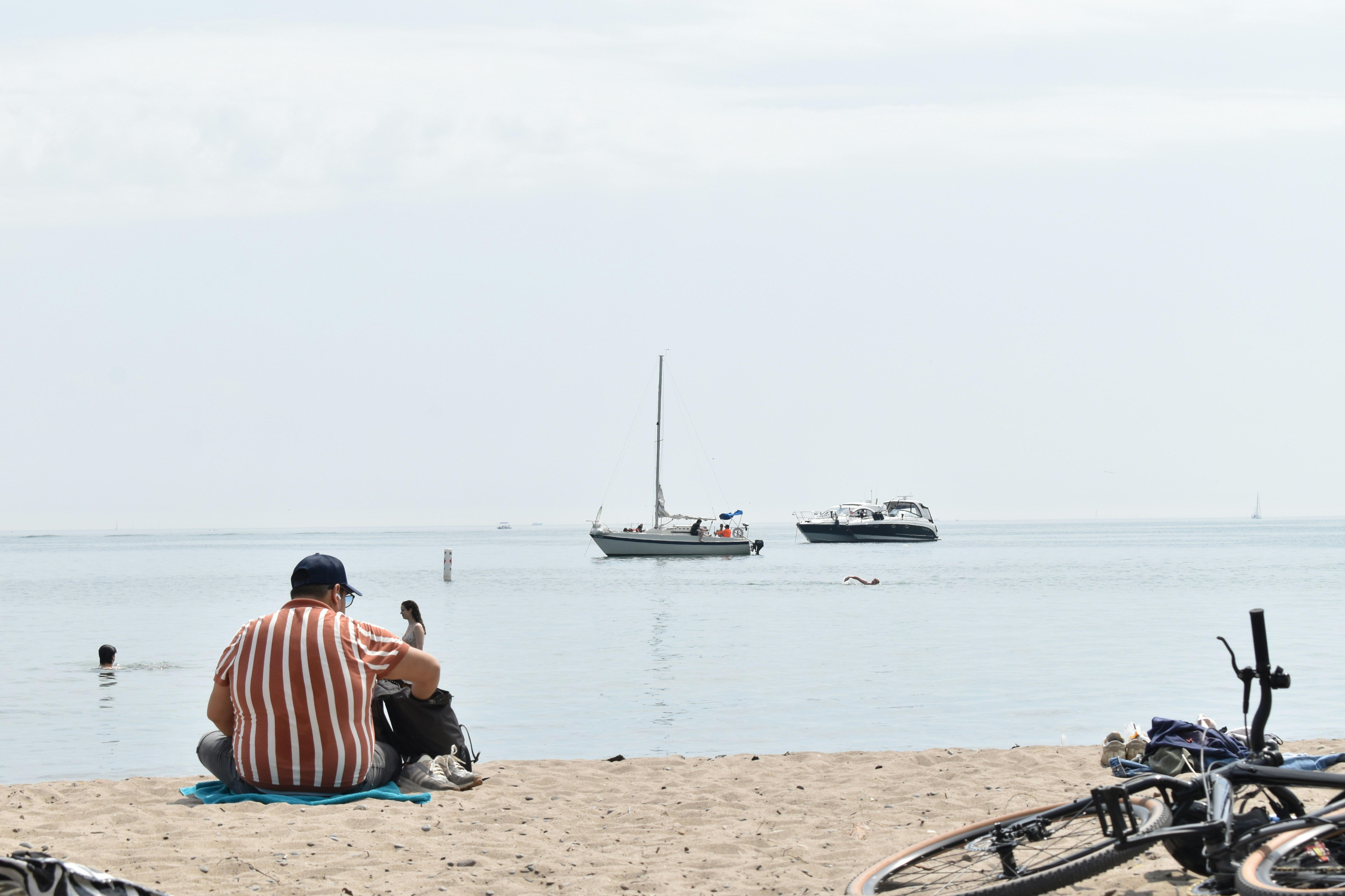 Stripes, Sand, and Sails: A Quiet Beach Moment with Bikes and Boats