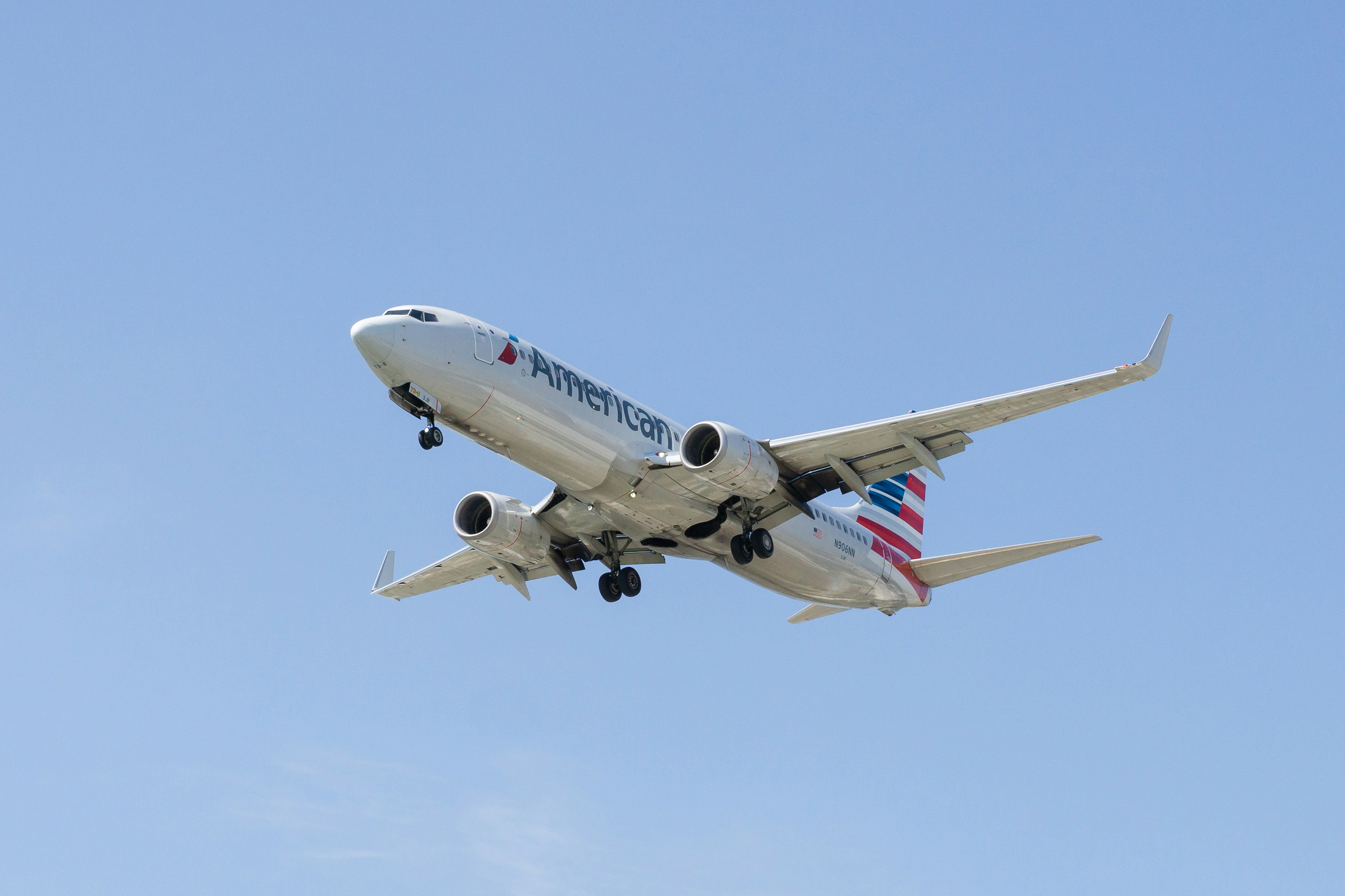 A large passenger jet flying through a blue sky photo – Free O'hare ...