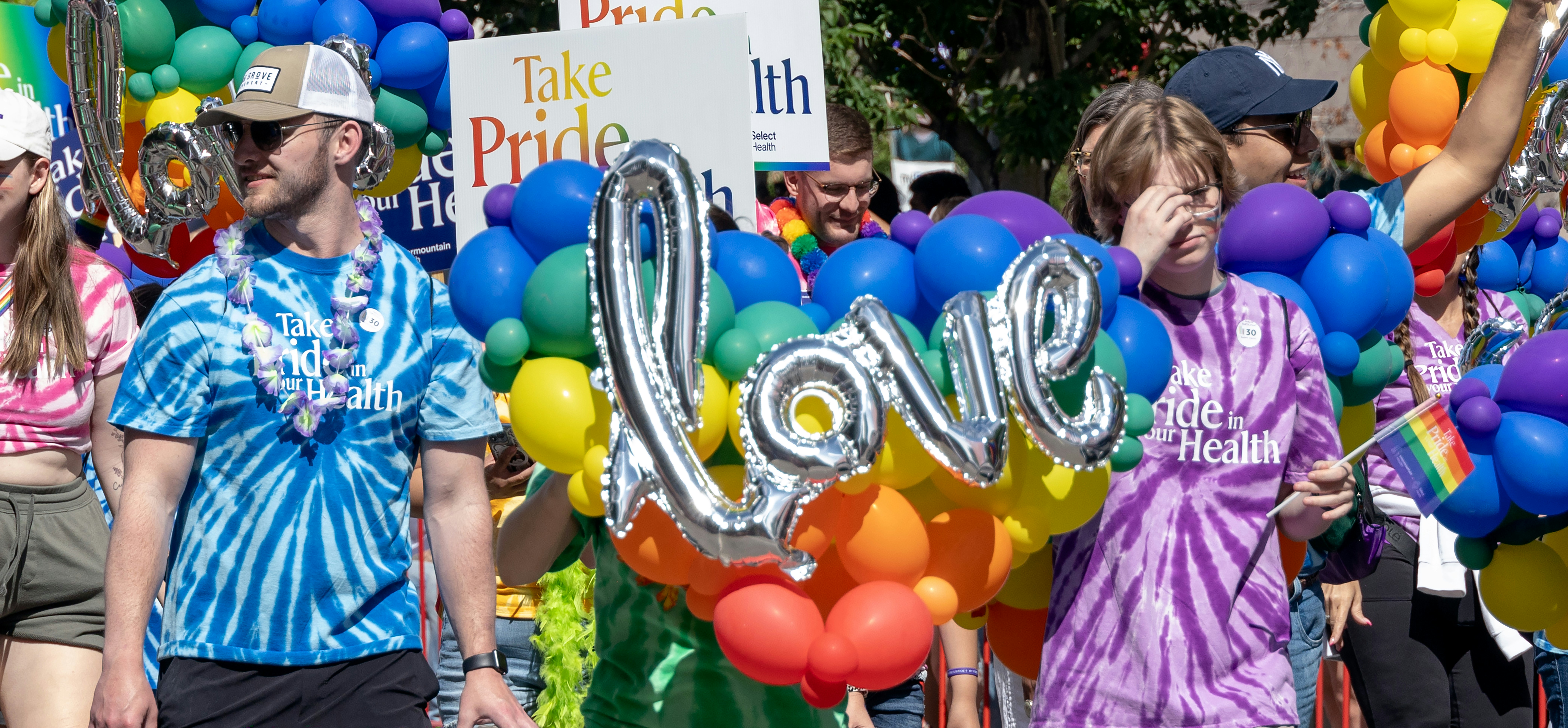 A group of people walking down a street with balloons in the shape of ...