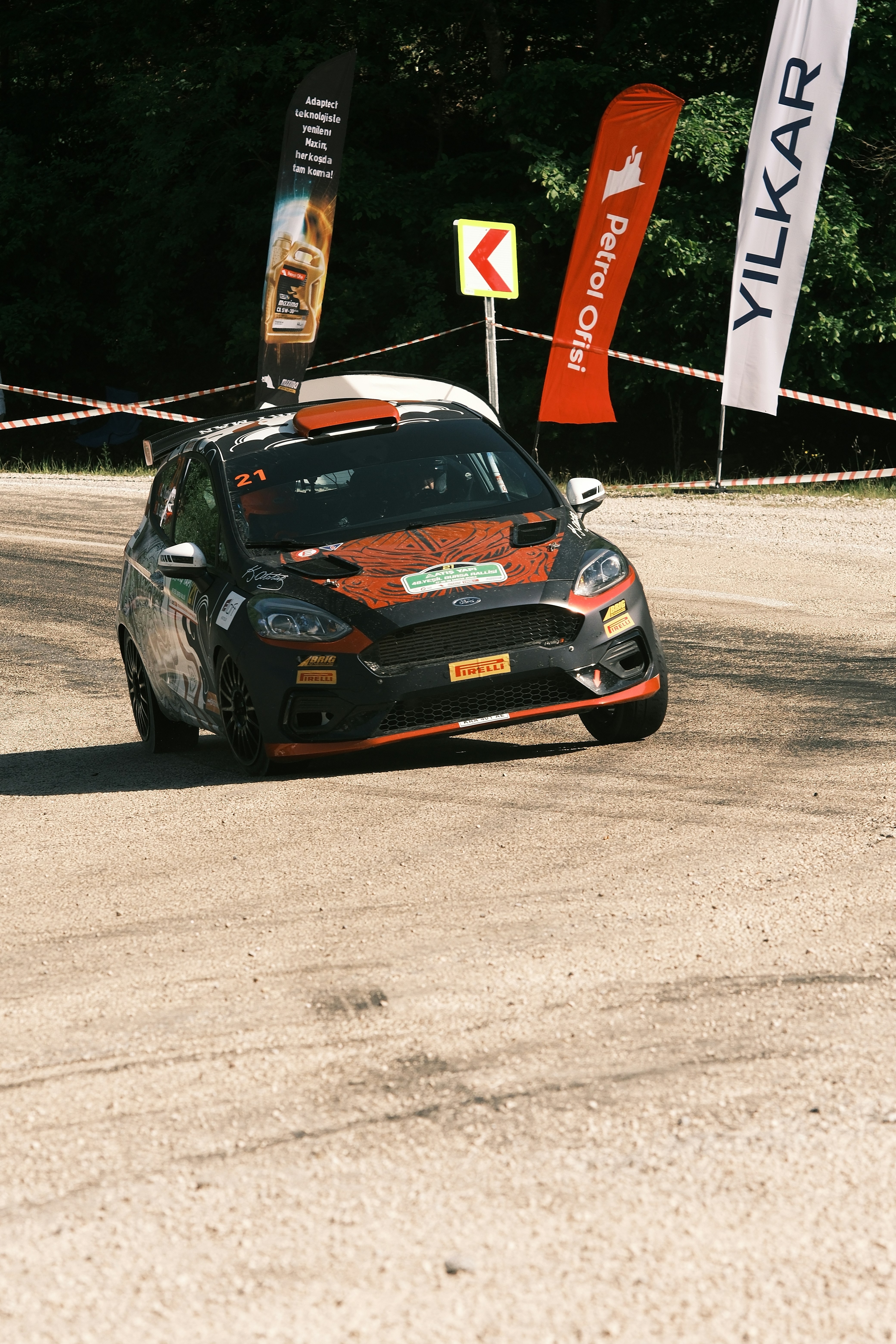 Dust-Splashed Drift: Rally Car Leans into a sunlit dirt bend under sponsor banners