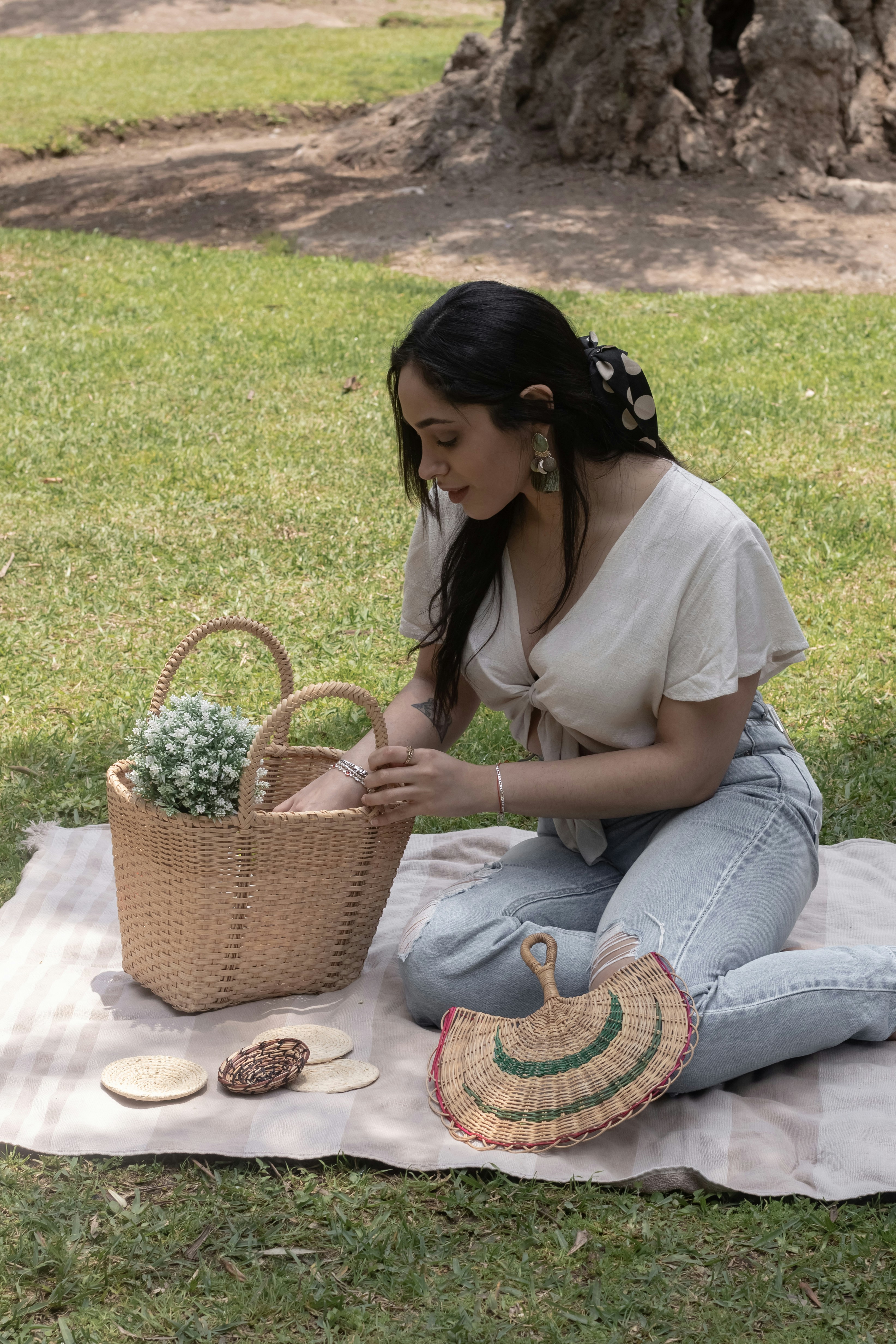 Sunlit Picnic Quietude: A Woman Arranges Blooms from a Wicker Basket