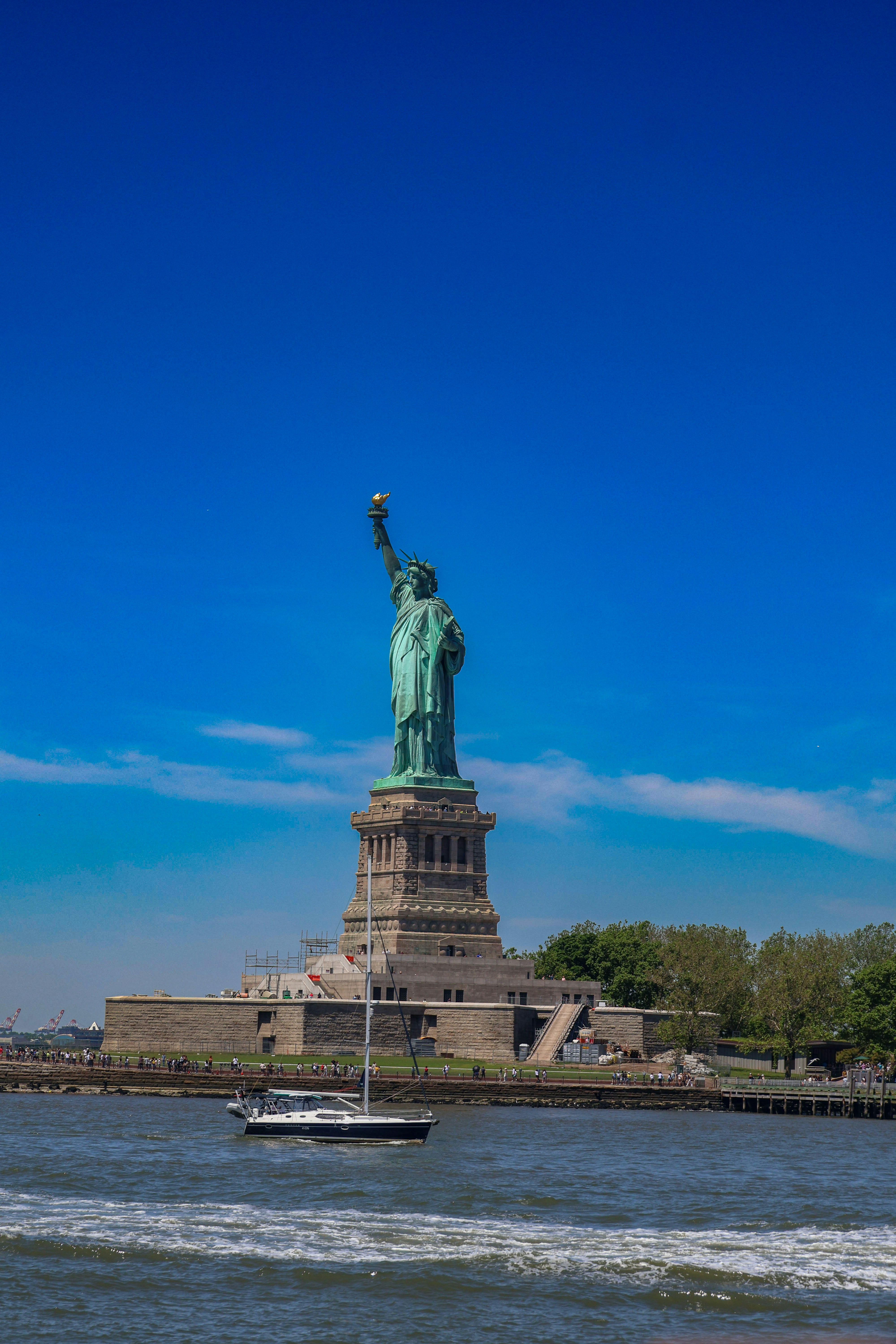 A boat is in the water near the statue of liberty photo – Free New york ...