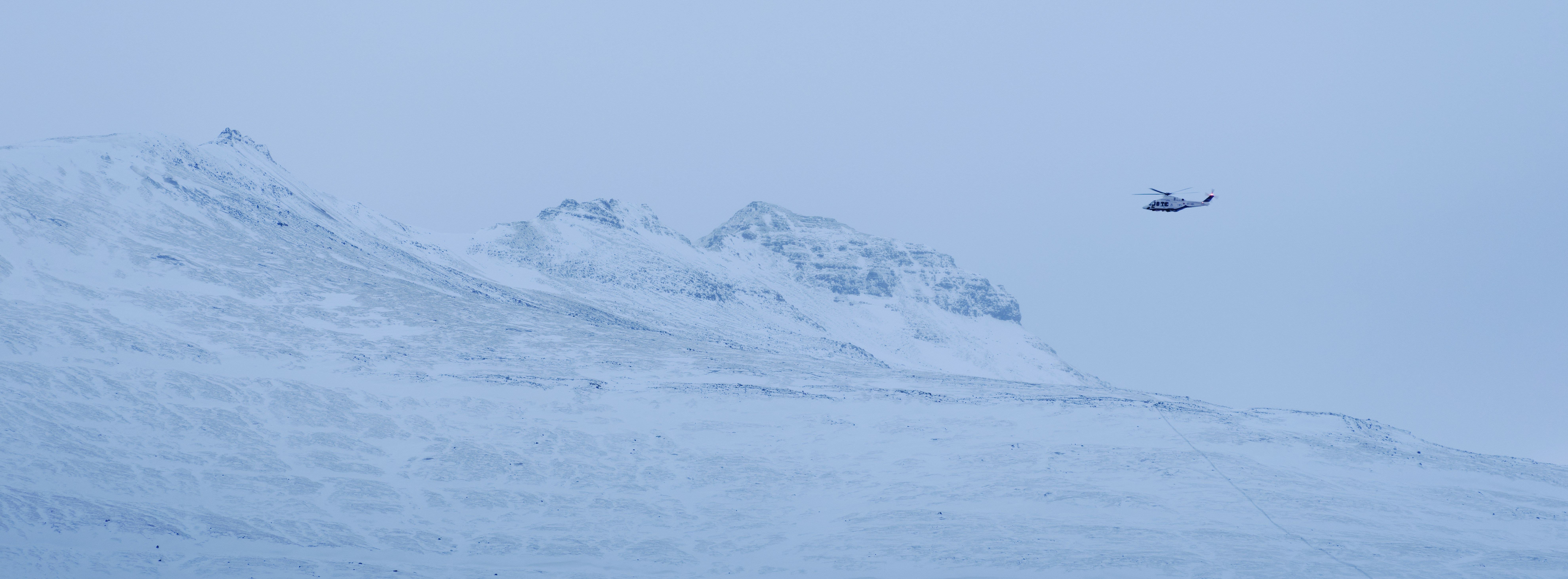 A helicopter flying over a snow covered mountain photo – Free Blue ...