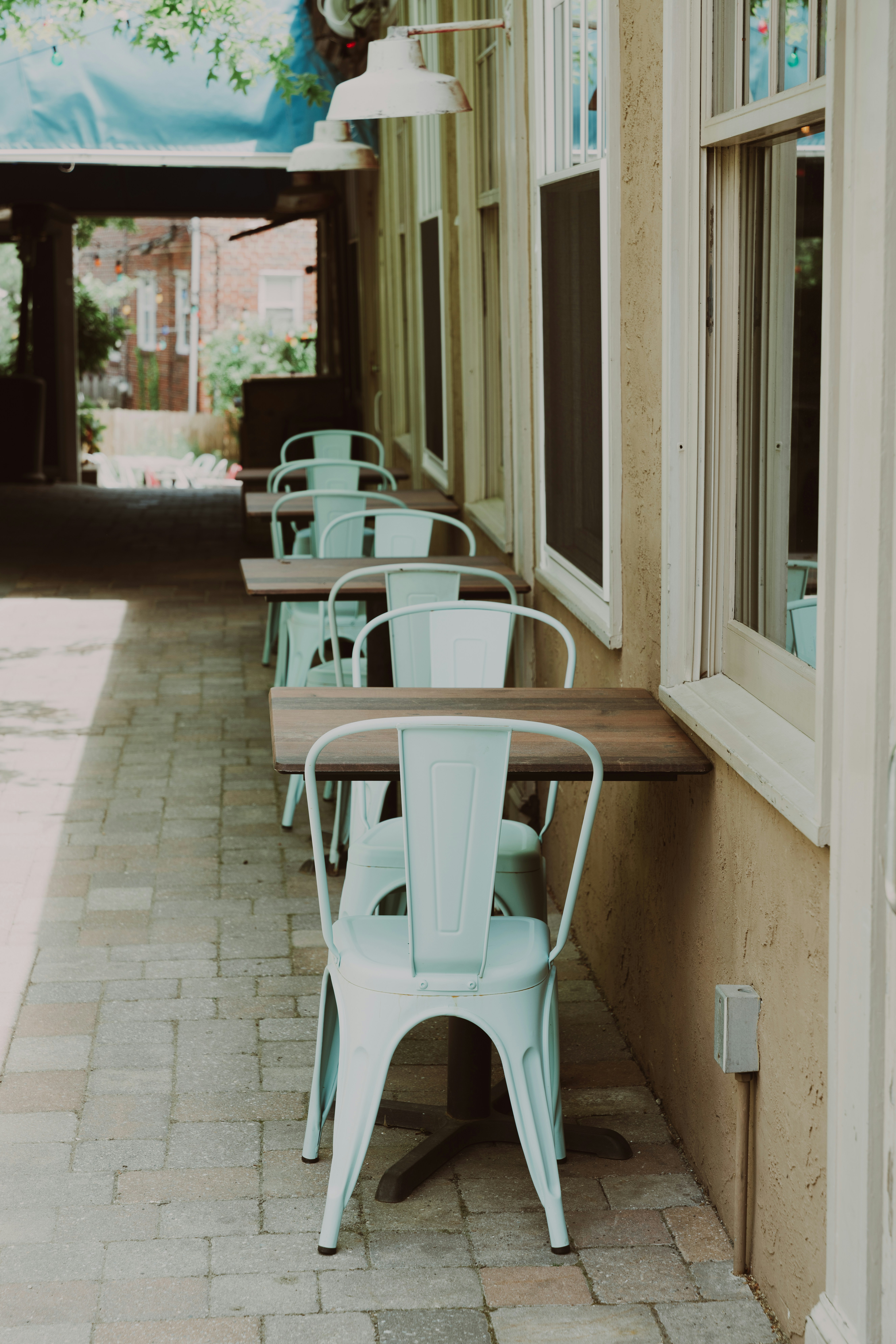 Minted Chairs Line a Sunlit Café Alley
