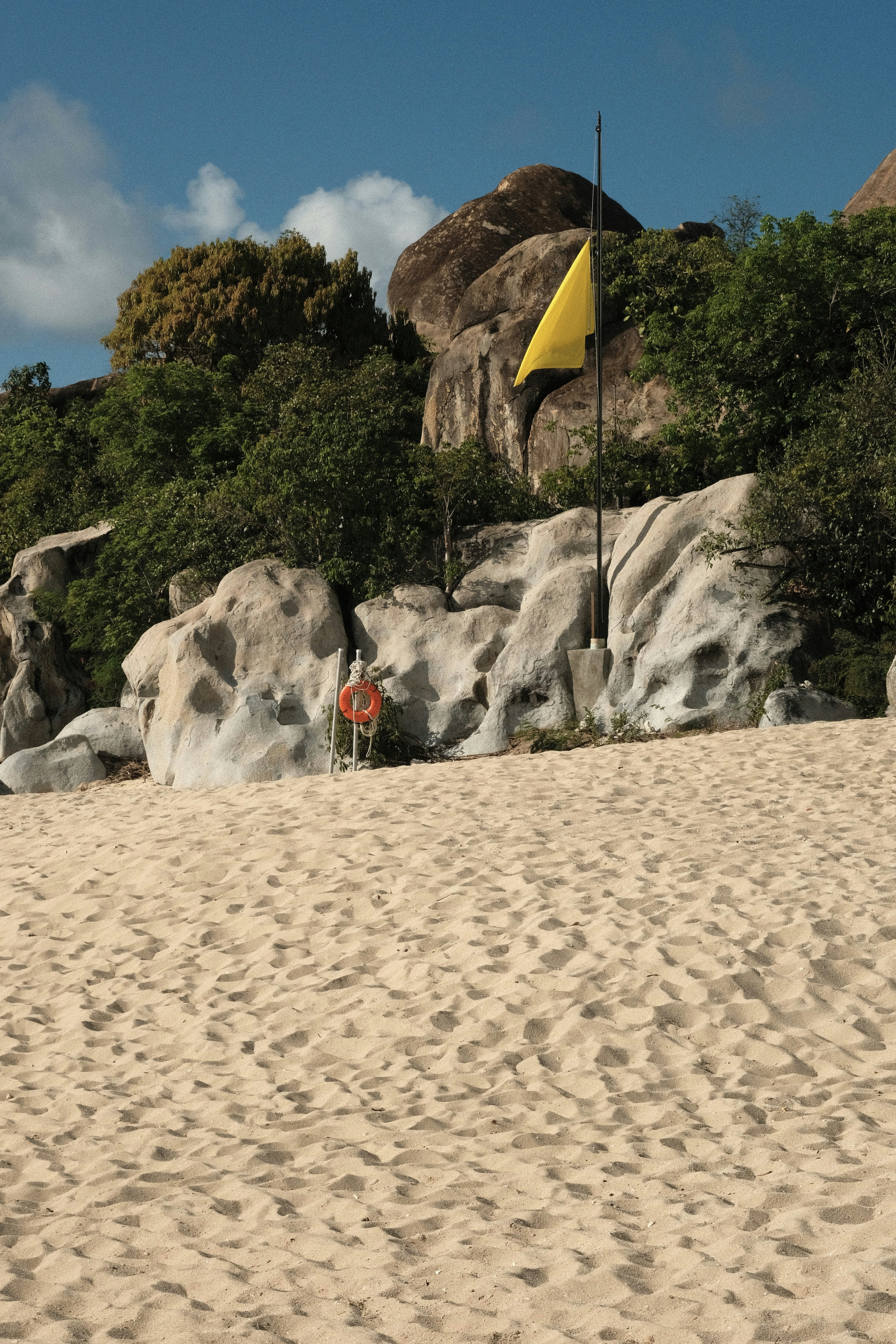 Yellow Flag Above Weathered Granite on a Sunlit Beach