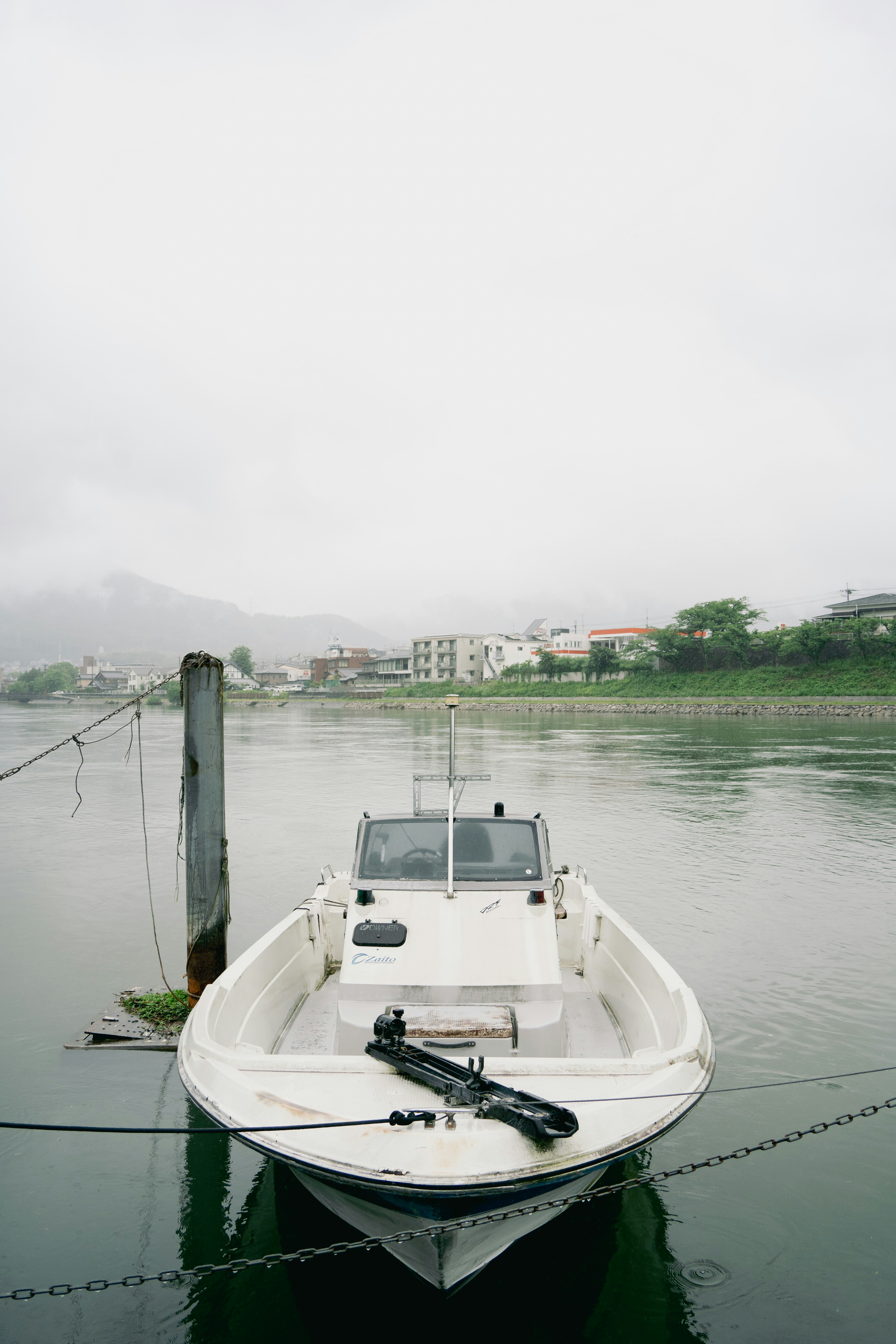 Anchor in Silence: White Boat Resting Along a Misty Riverfront