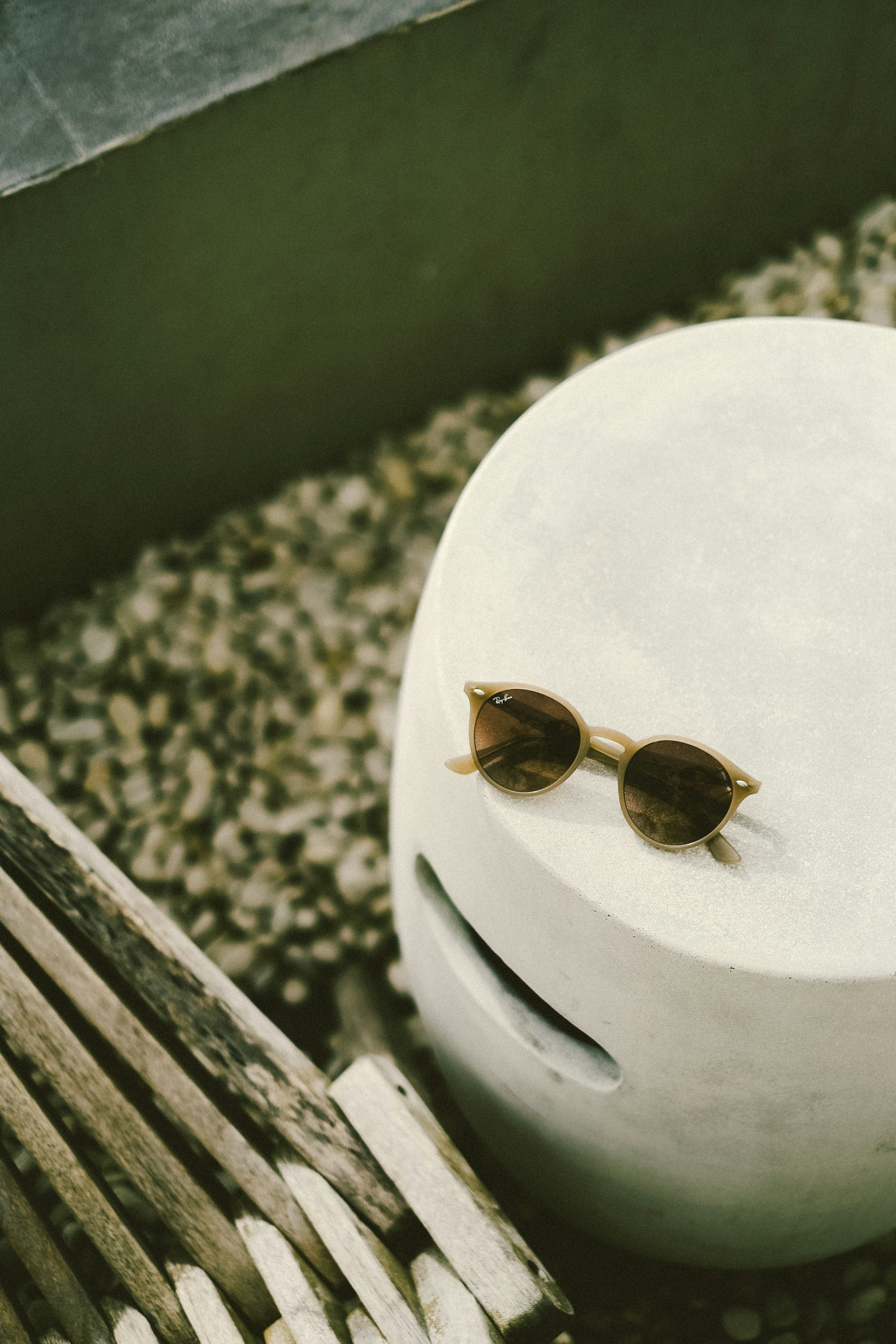 Whispered Retro: Sunglasses on a sun-warmed pedestal amid weathered slats