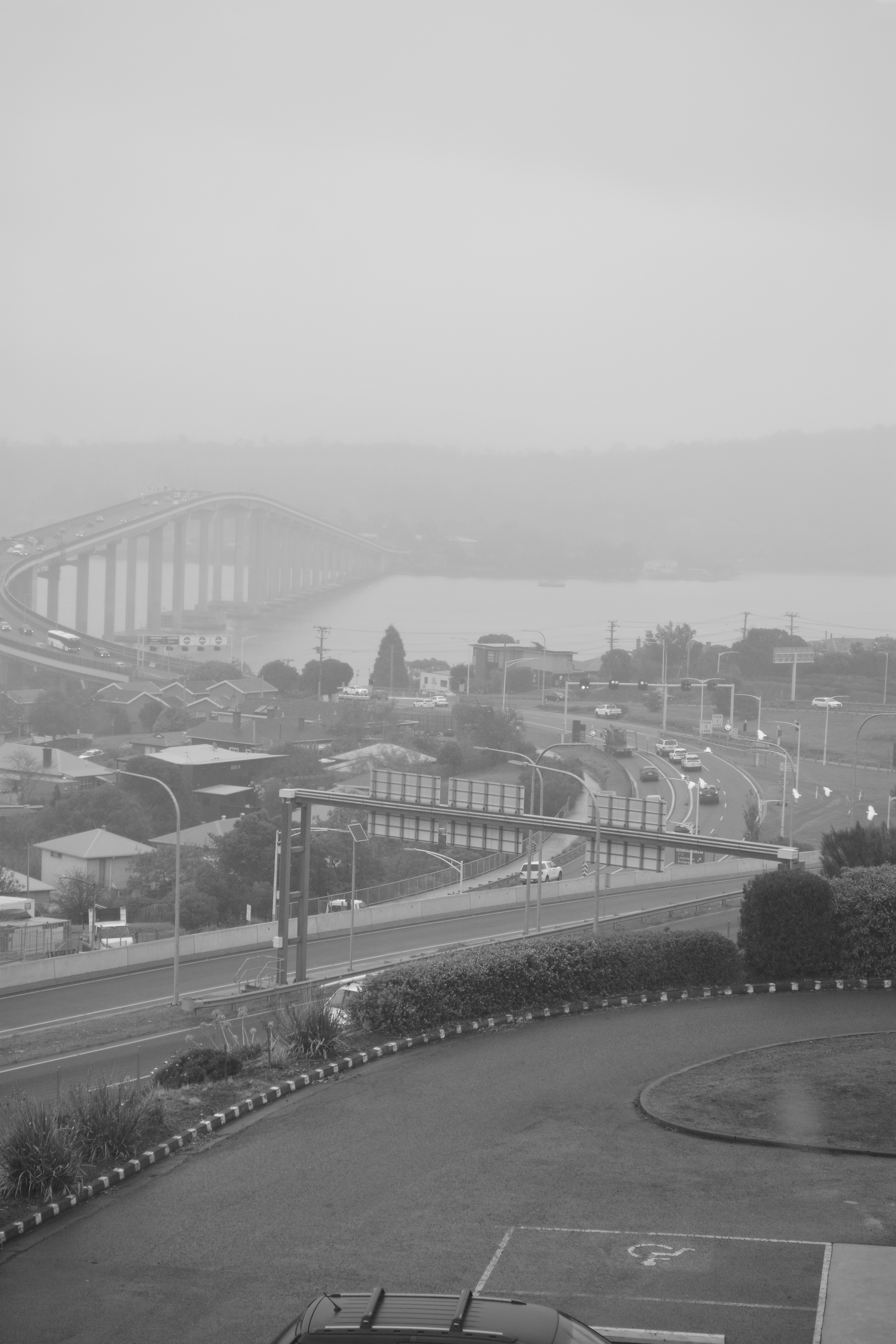 Arch in the Mist: Distant Bridge and Winding Roads in a Quiet Monochrome Cityscape