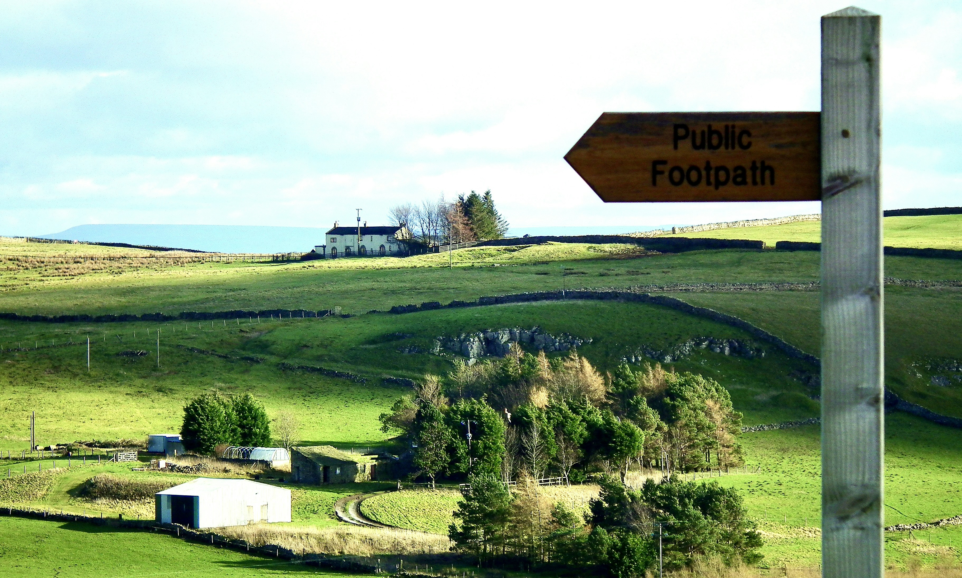 Footpath Sign Hangs Above a Quiet Countryside Scene
