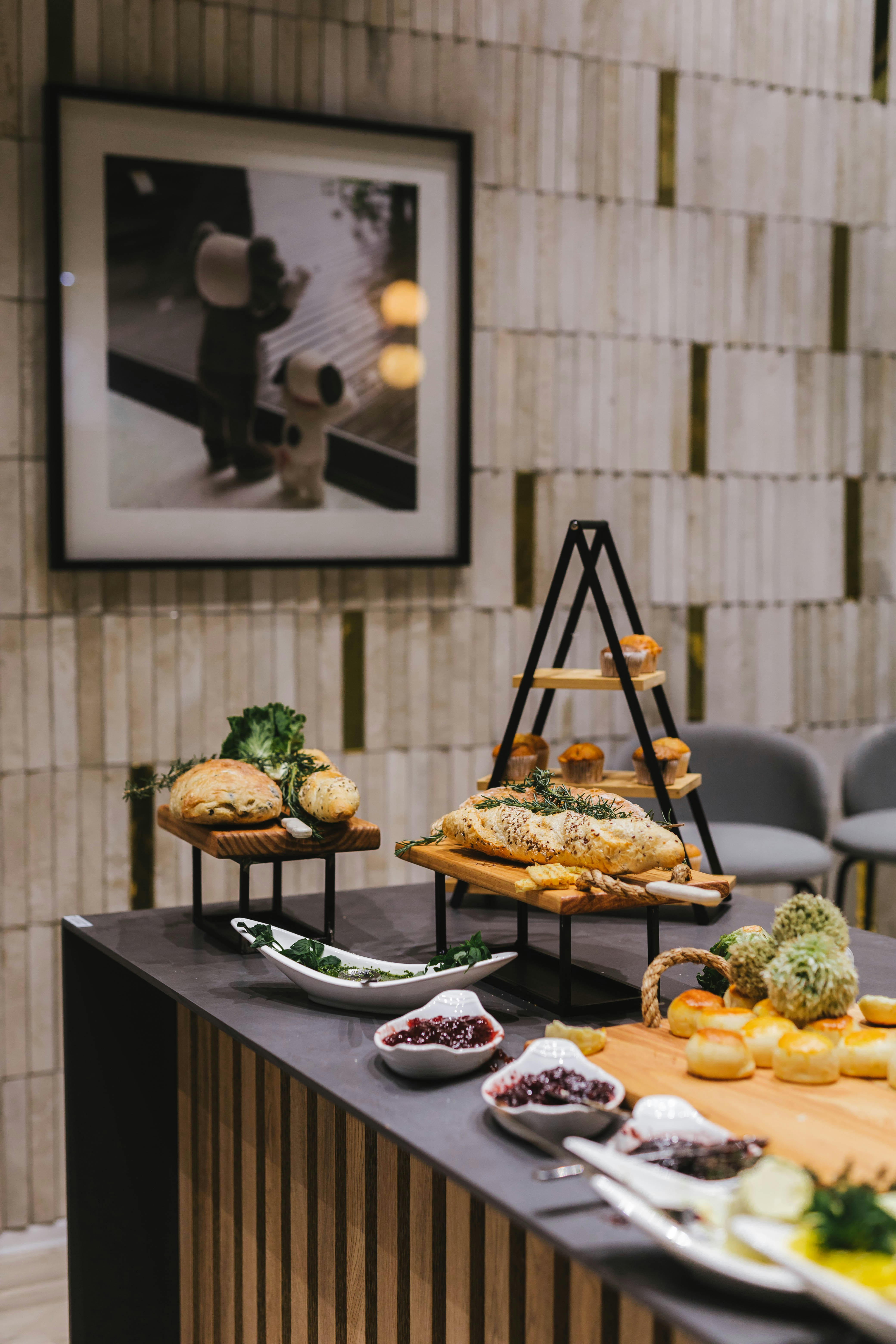 Artfully arranged pastries and fresh ingredients on a stylish table, complemented by a whimsical framed illustration in the background.