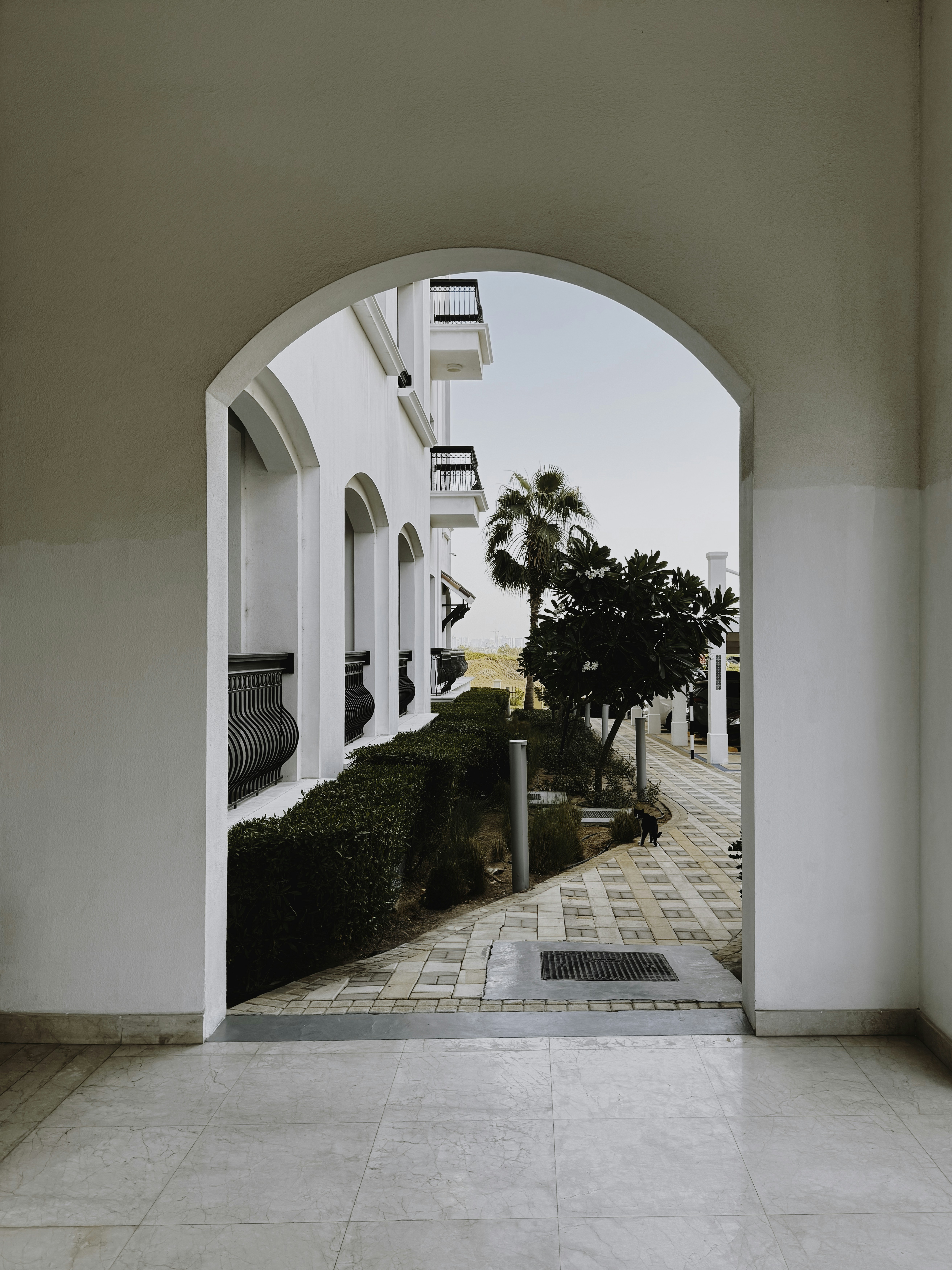 An archway leading to a building with a tree in the middle photo – Free ...