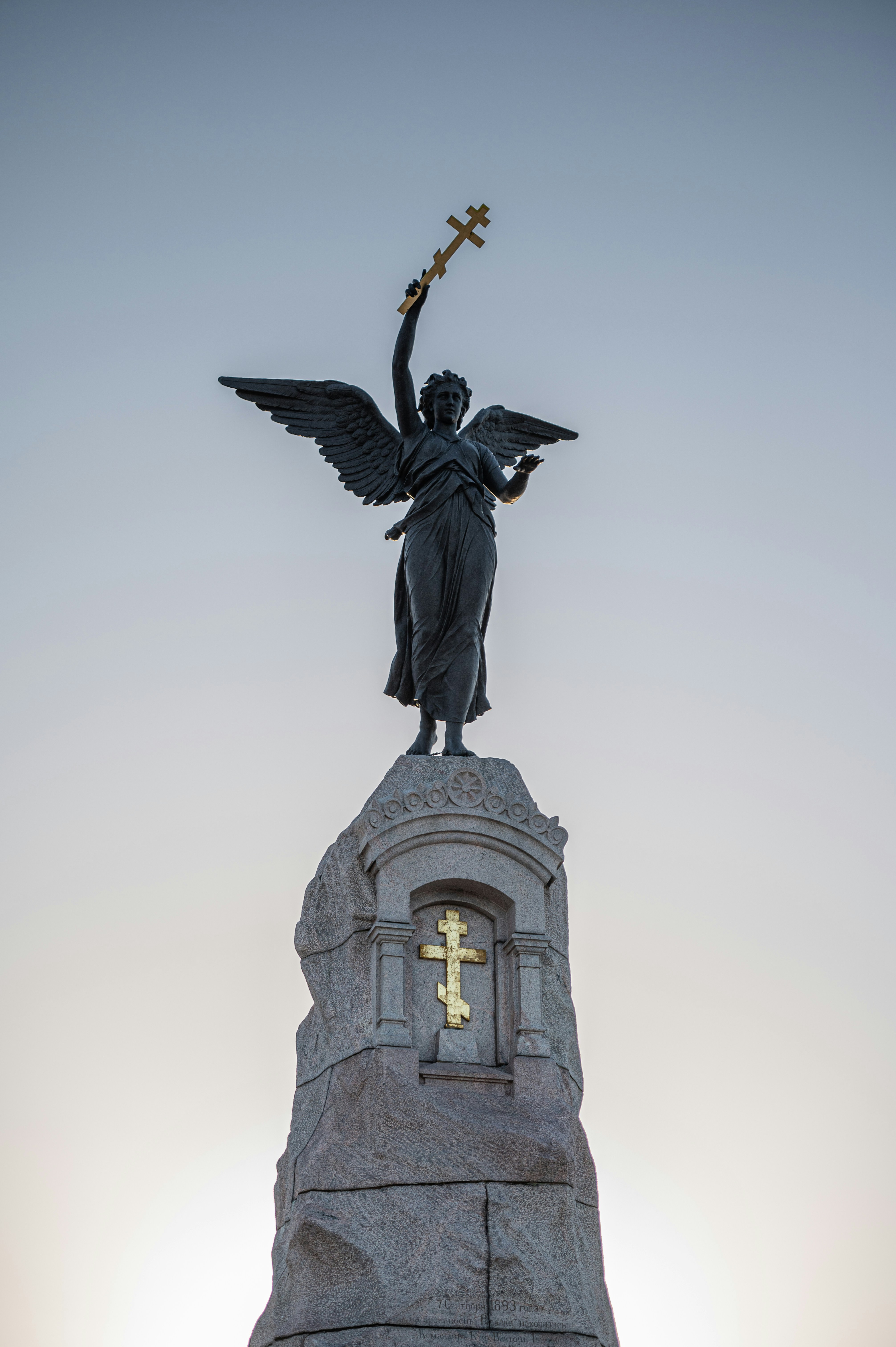 Cross-Bearing Angel Crowned by Dawn: Bronze Wings on a Stone Pillar