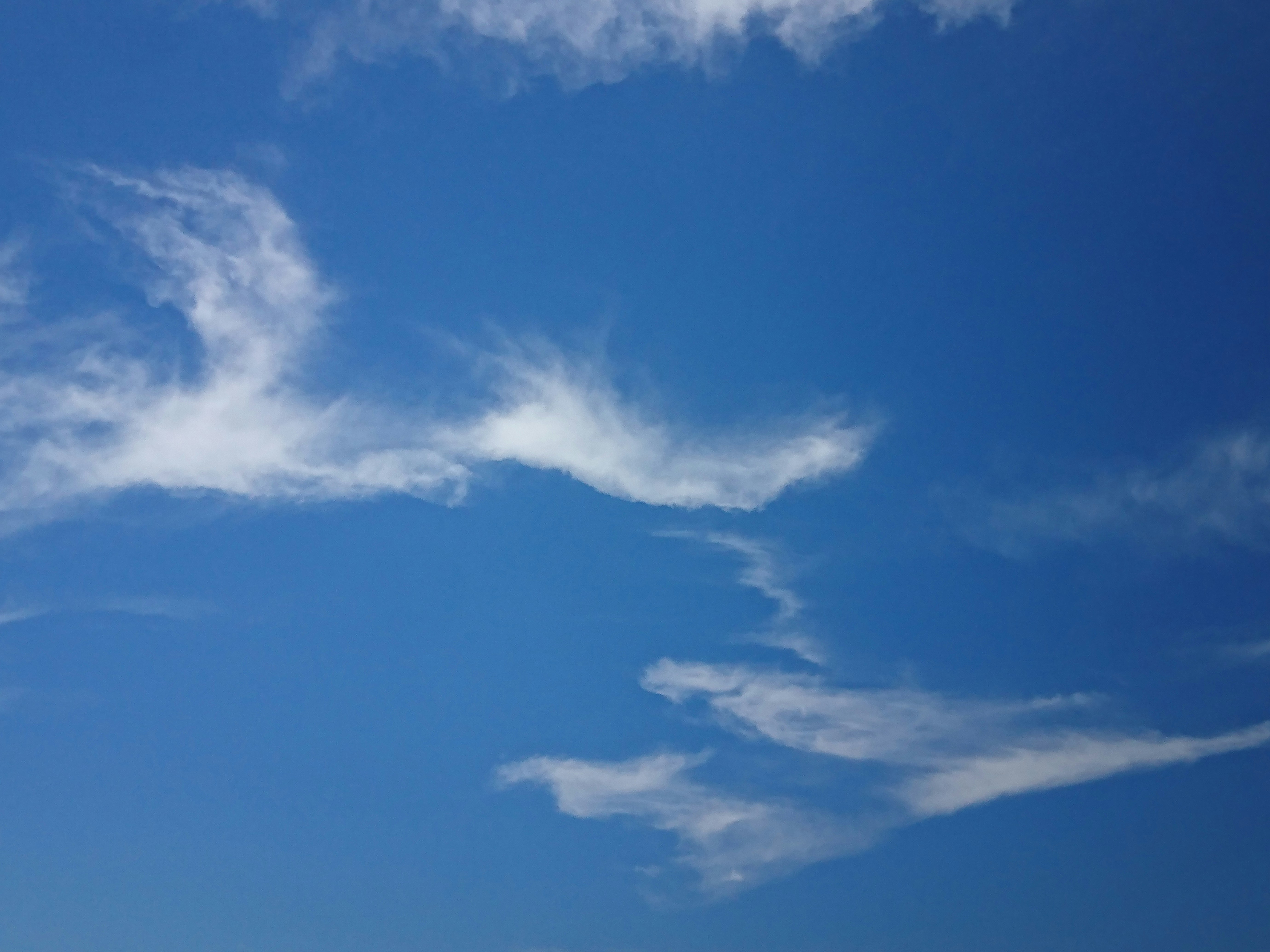 Clear blue sky with wispy cirrus clouds drifting across the frame.