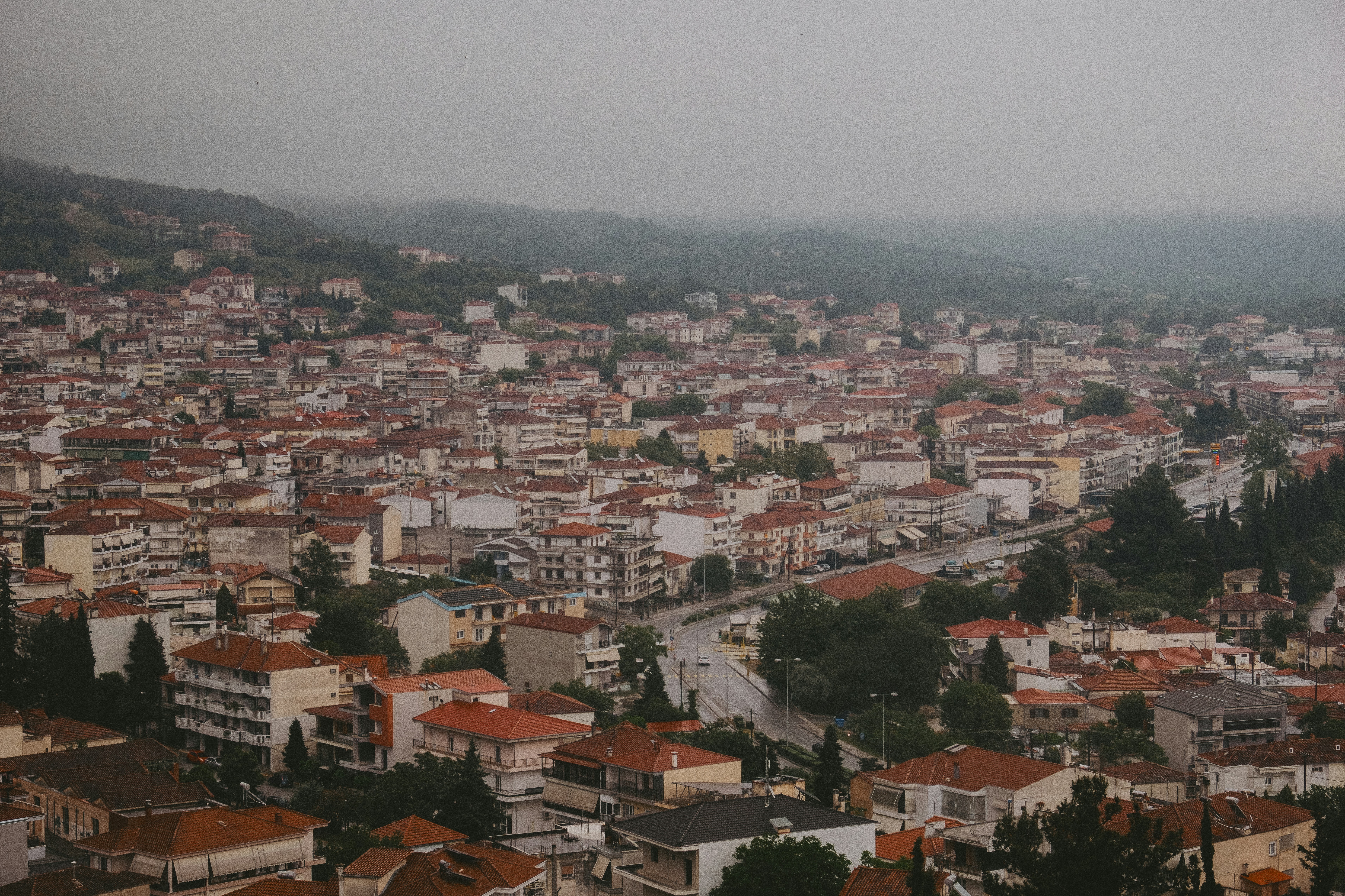 Hillside town with red-roofed buildings enveloped in mist.