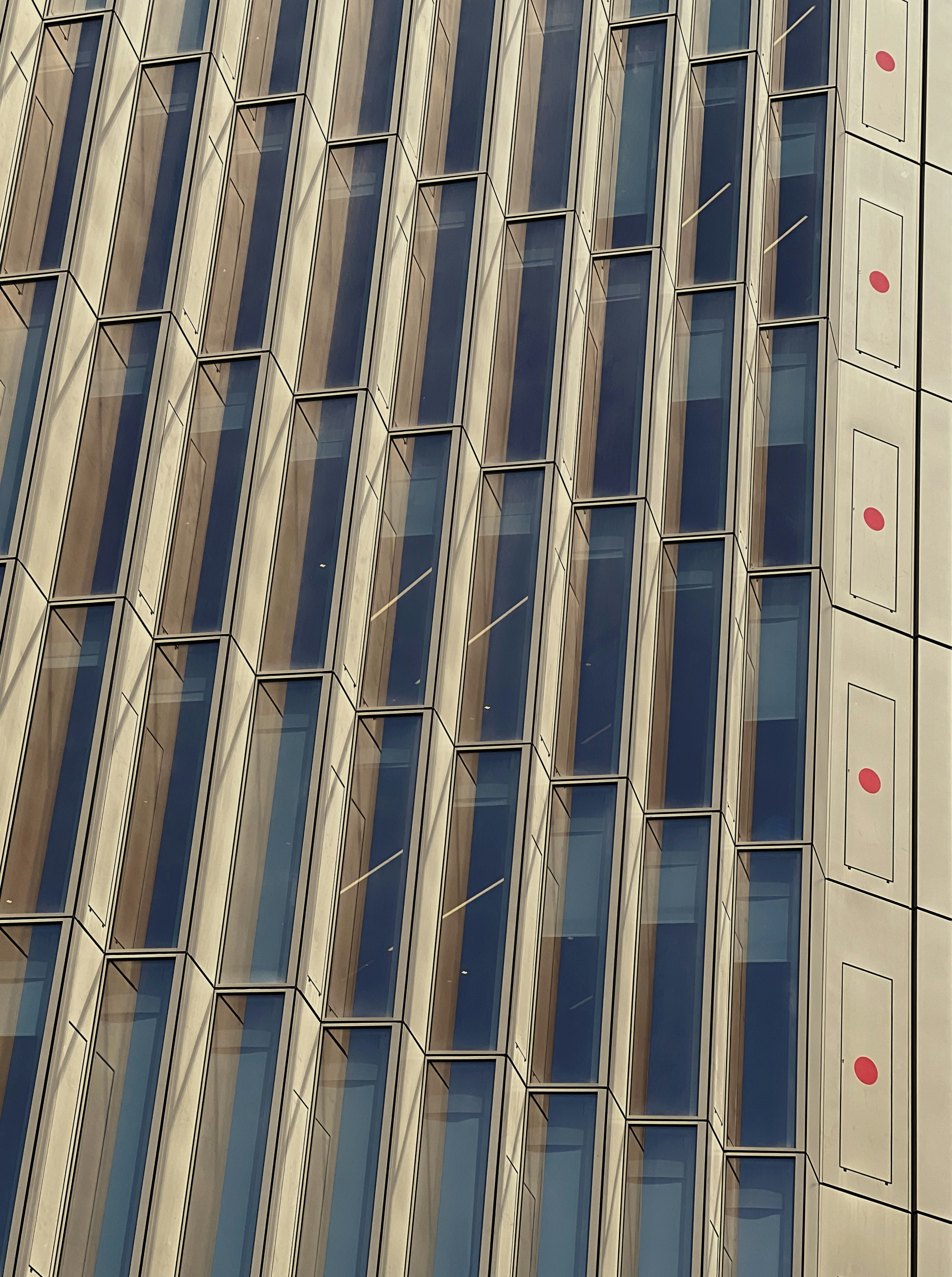 Sunlit Facade Rhythm: Vertical Glass Strips on a Beveled Building