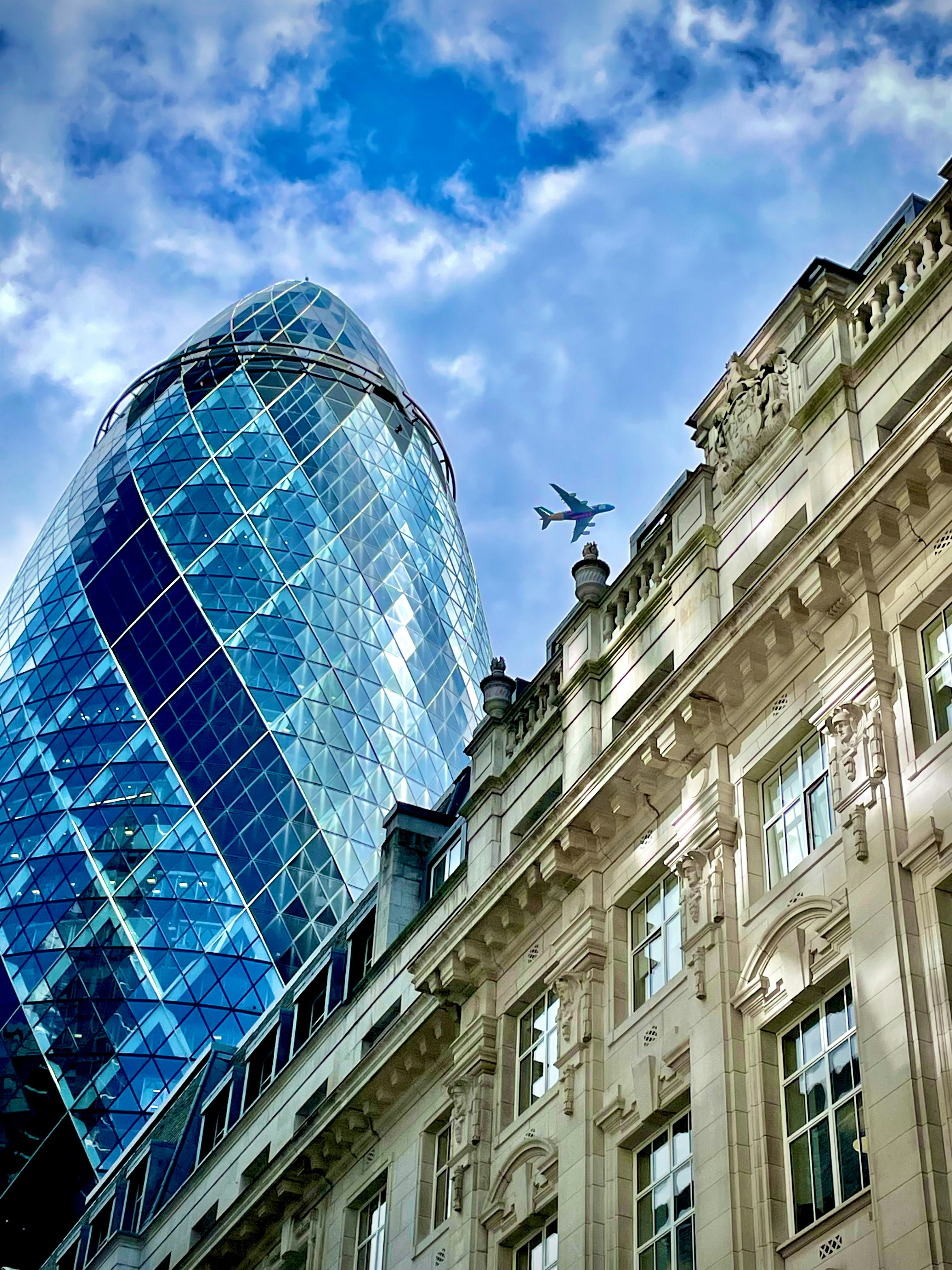 Urban Skyward: The Gherkin Reflecting the Sky Above a Classical Facade