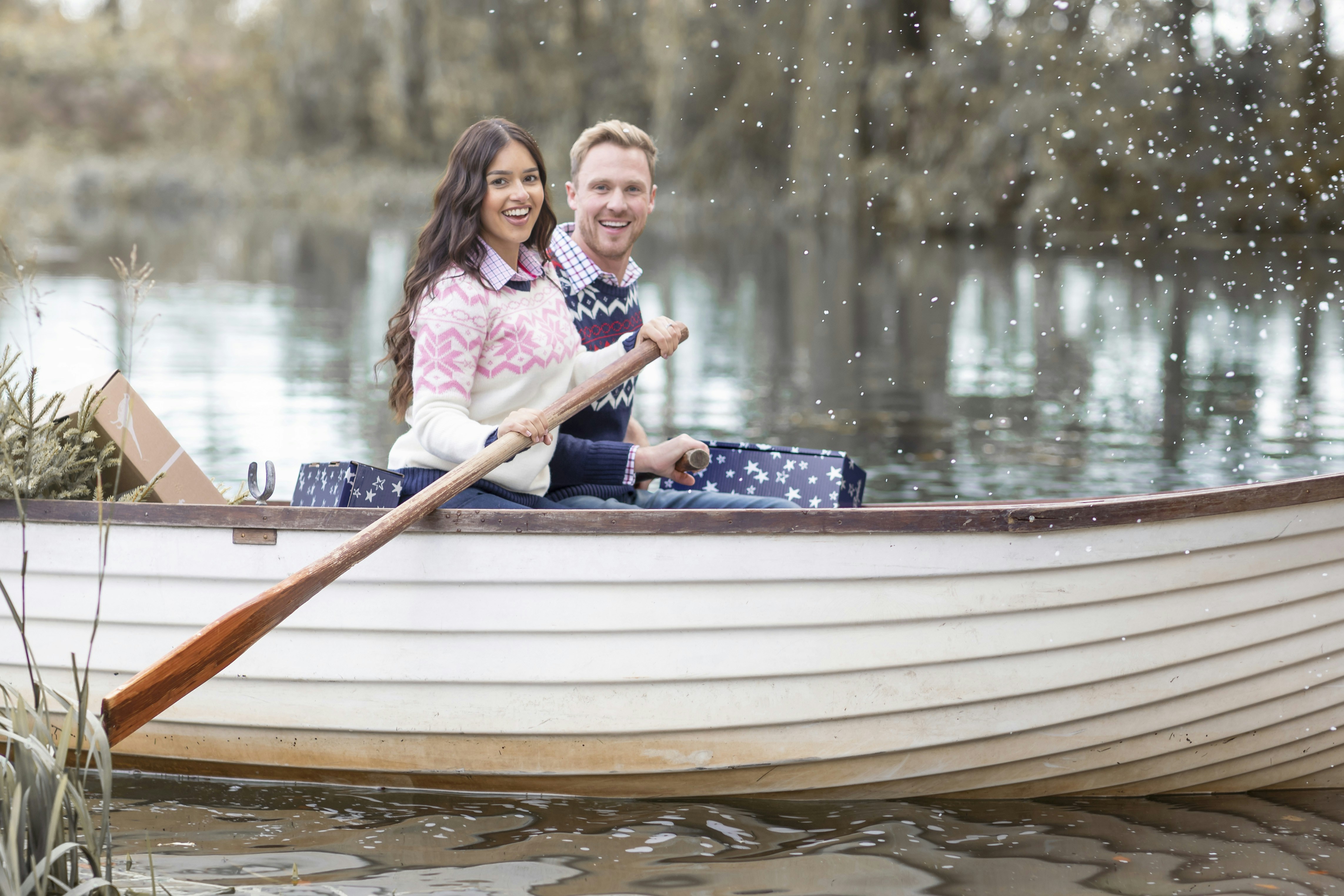 Women wearing Christmas jumper holding a oar | a man and a woman in a boat on the water
