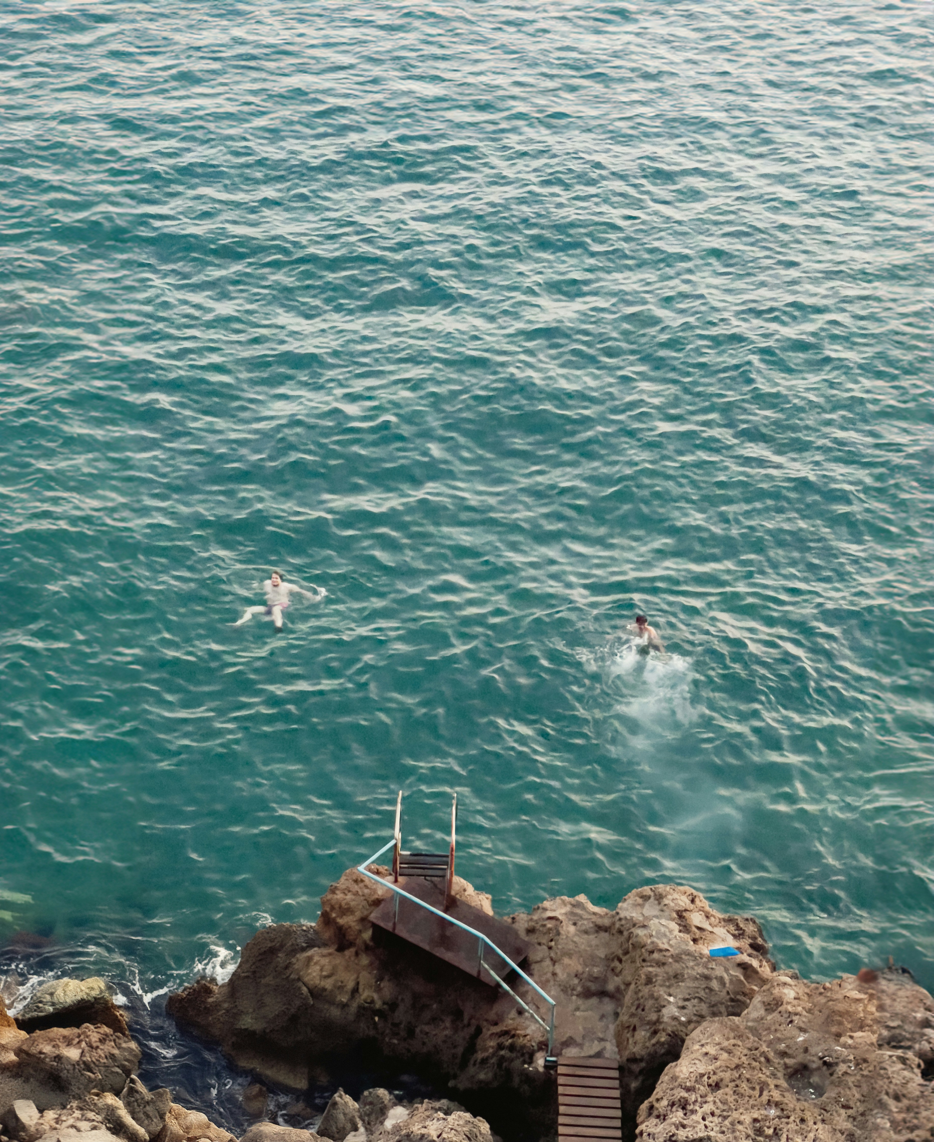 Teal Currents: Two Swimmers near the Rocky Staircase