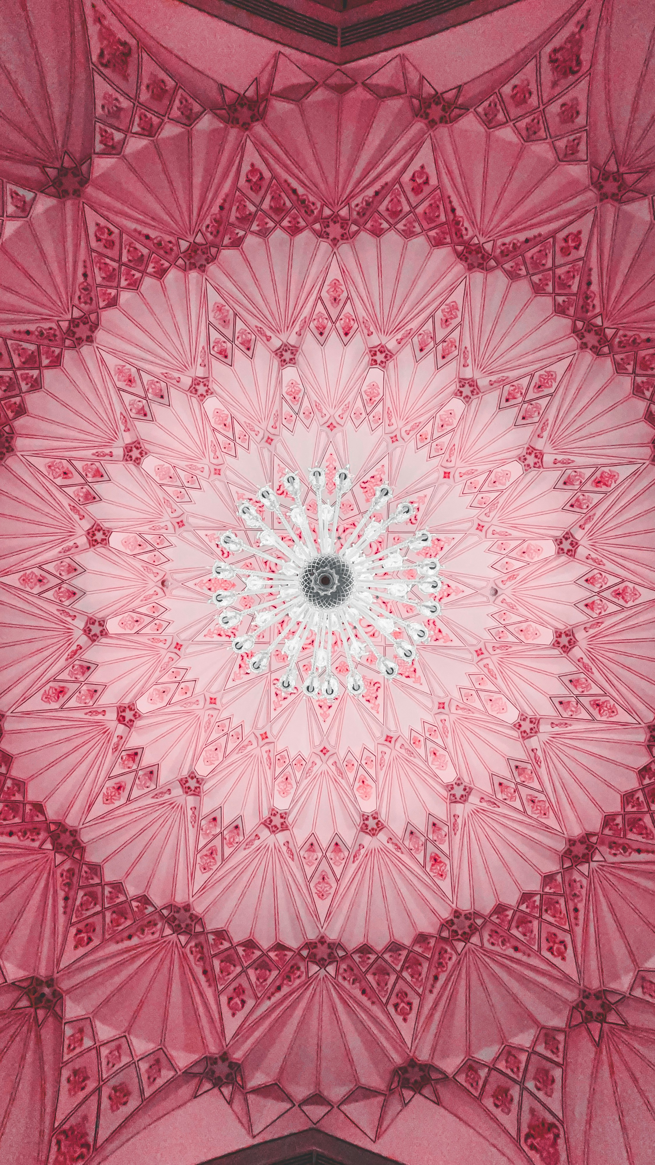 Crystalline Center: A Pink Geometric Dome Enshrines a Chandelier