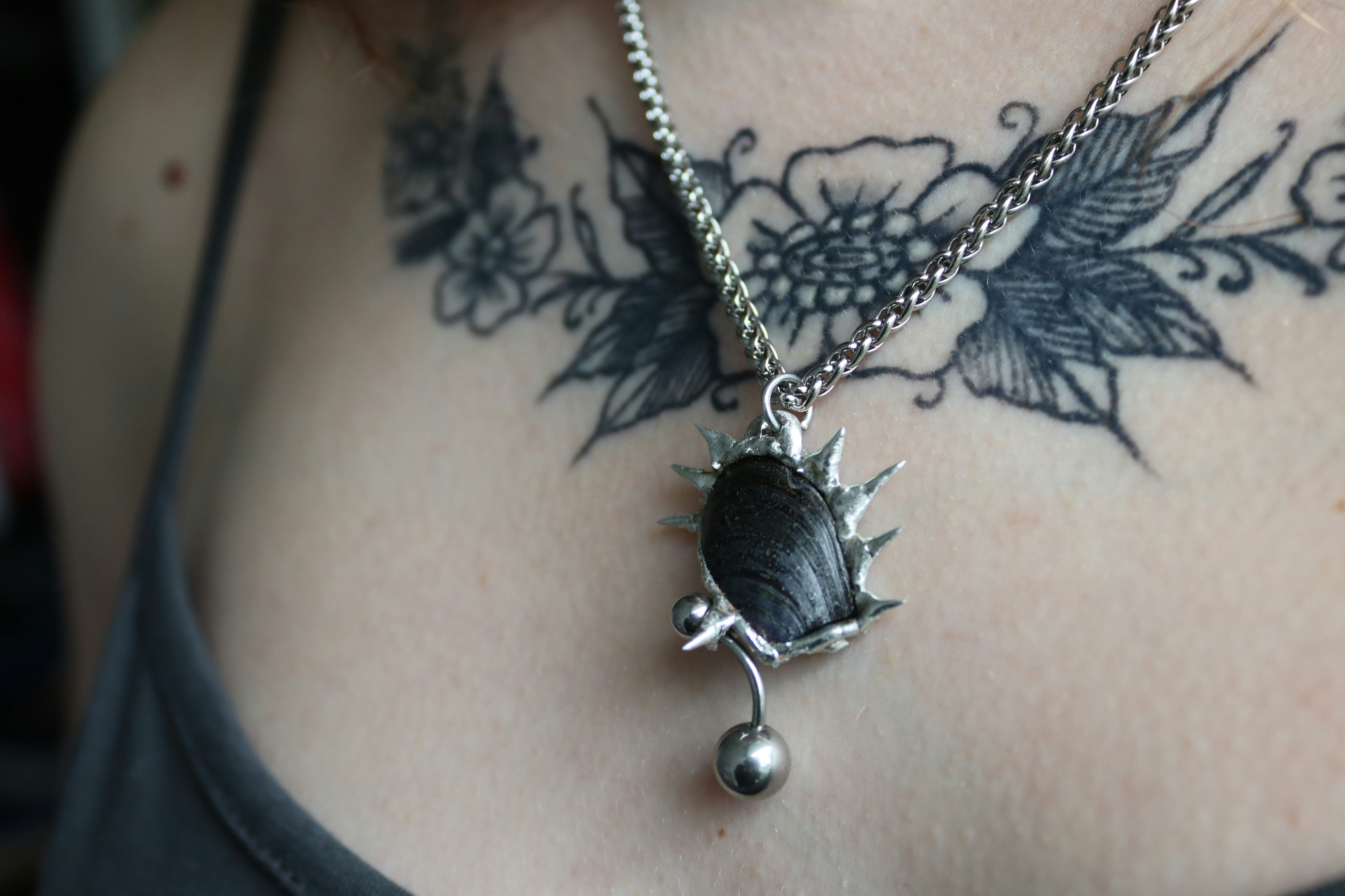 Spiked Heart Pendant Resting Against Tattooed Chest