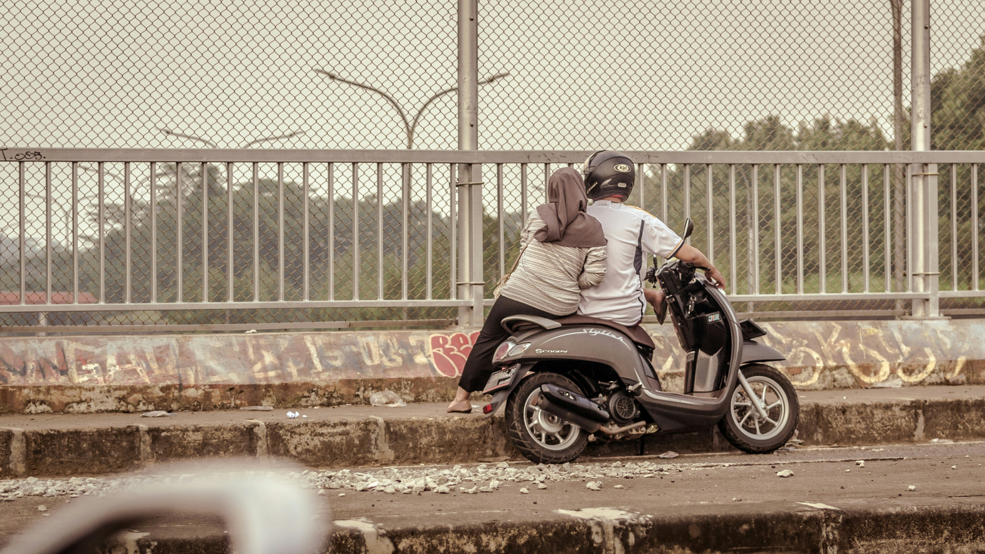 Scooter Duo gliding along a graffiti-etched overpass