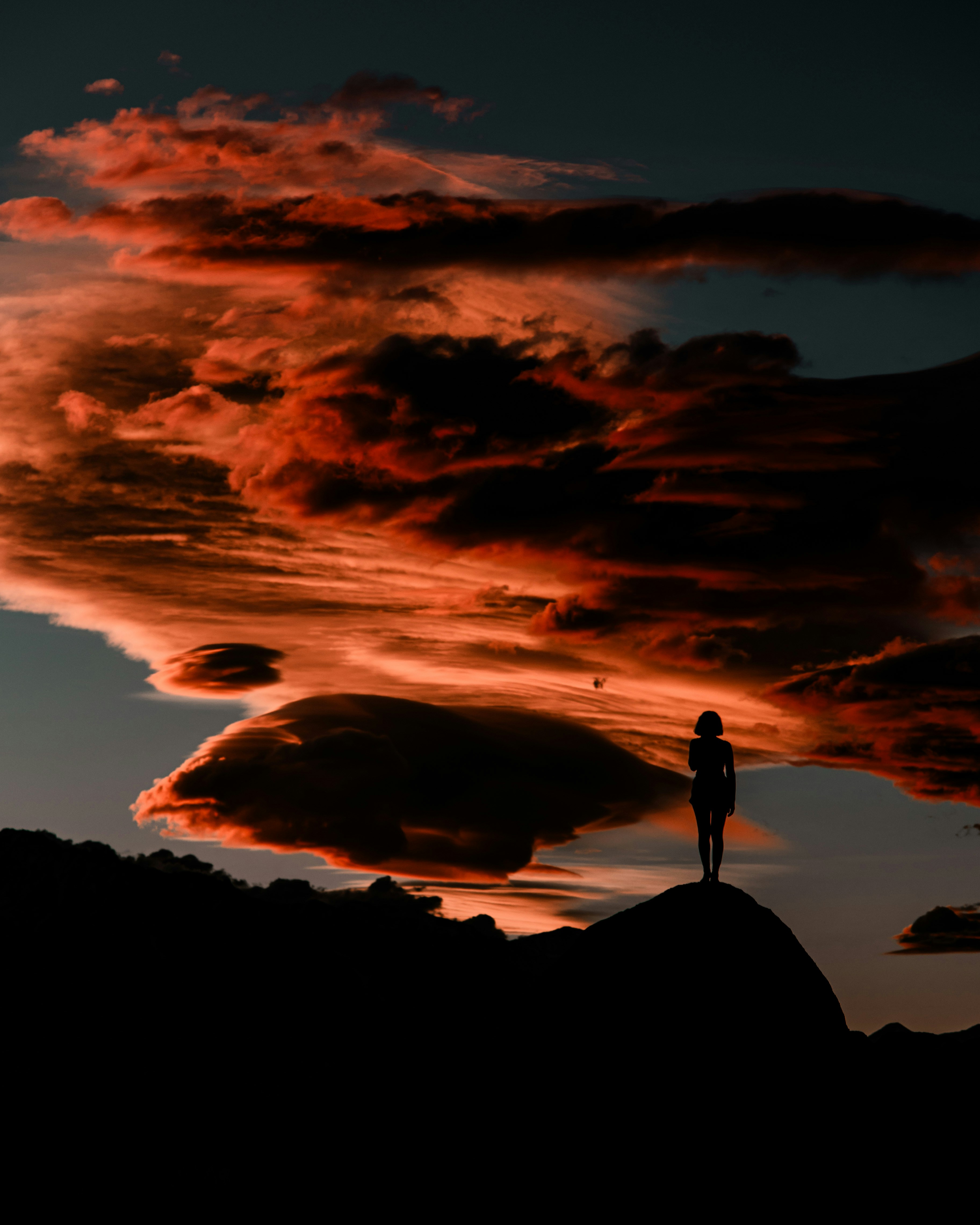 Lone Silhouette on a Rocky Promontory Beneath Molten Clouds at Sunset